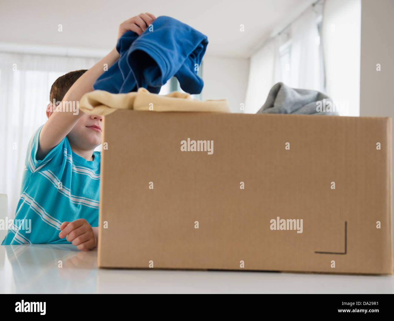 Boy (4-5) putting clothing into box Stock Photo - Alamy