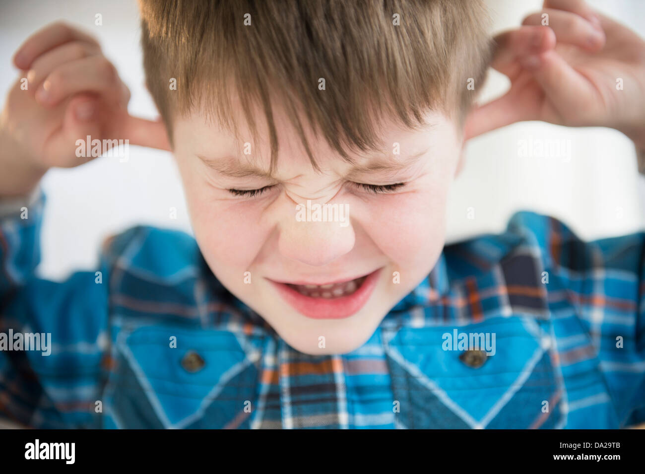 Portrait of boy (4-5) sticking fingers in his ears Stock Photo - Alamy