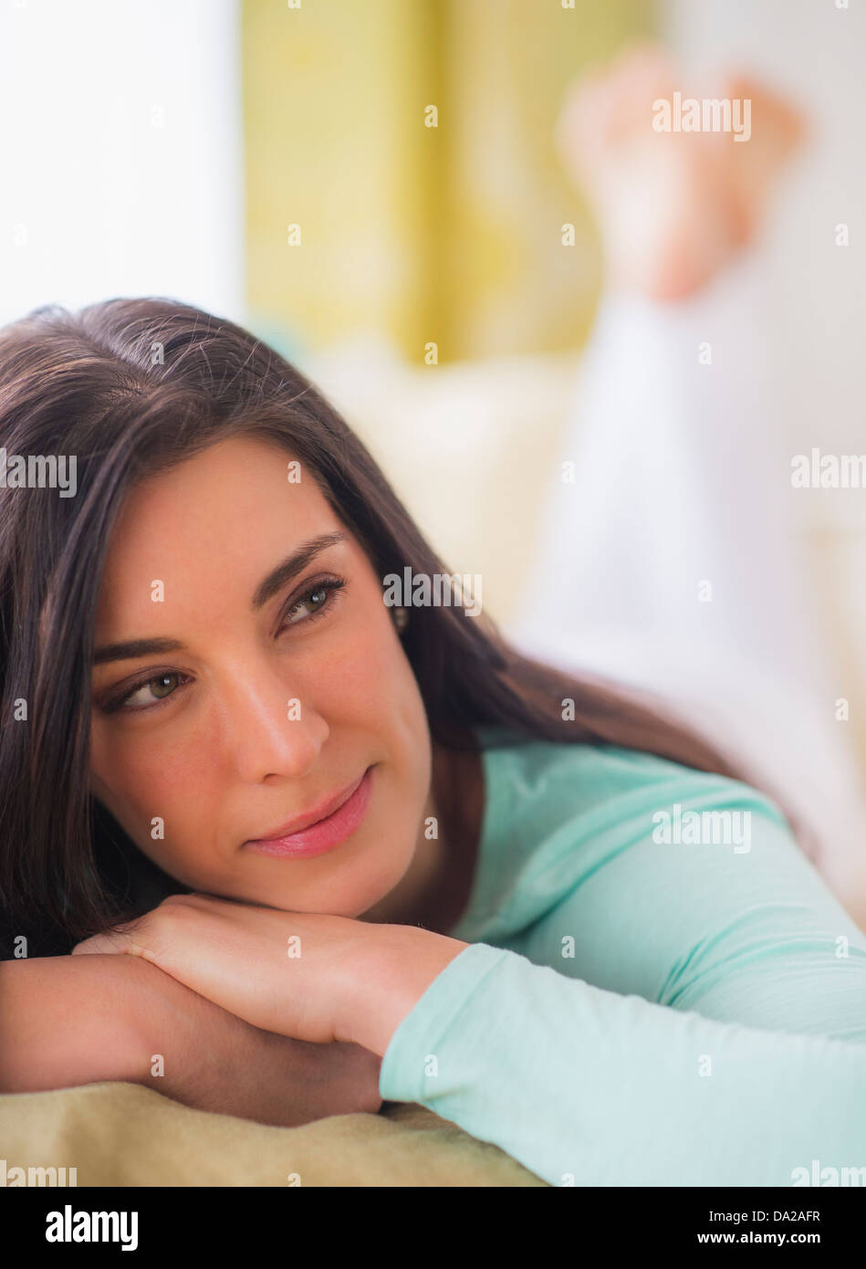 Portrait of woman lying down on bed with hand on chin, Looking away ...