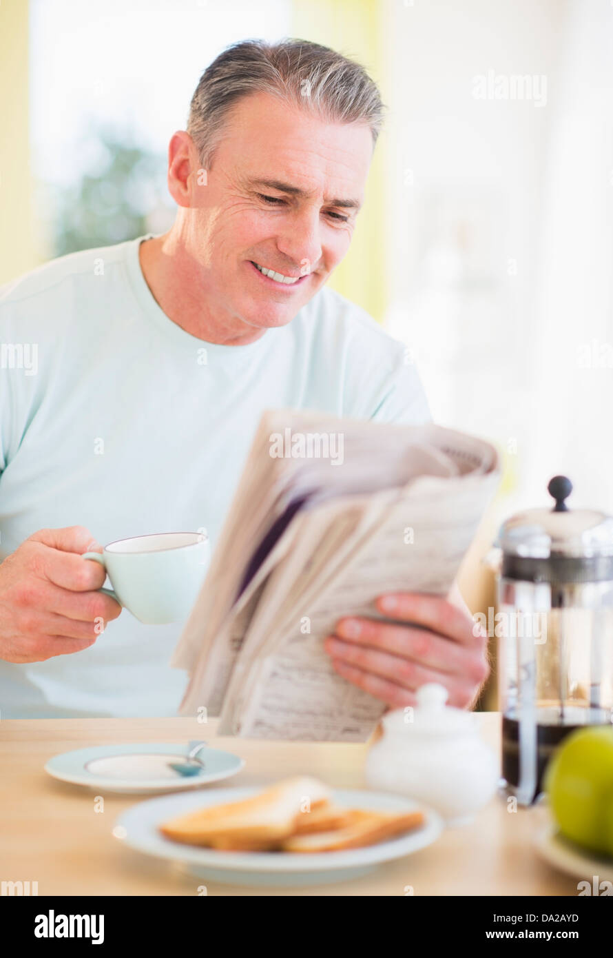 Portrait of man reading newspaper and having breakfast Stock Photo - Alamy