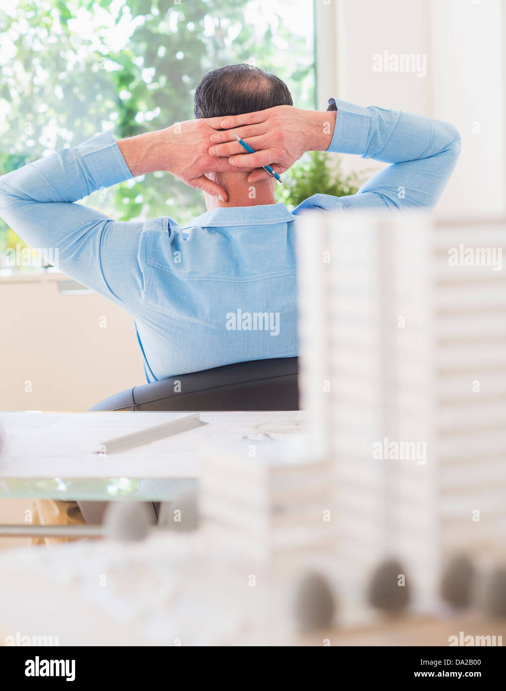 Rear view of man sitting in office Stock Photo - Alamy