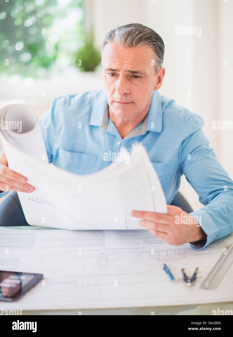 Portrait of man looking at blueprints in office Stock Photo - Alamy