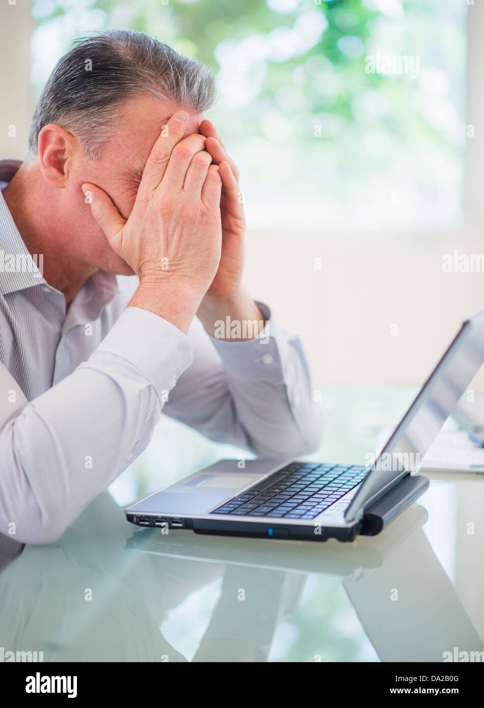 Portrait of tired man working on laptop Stock Photo - Alamy