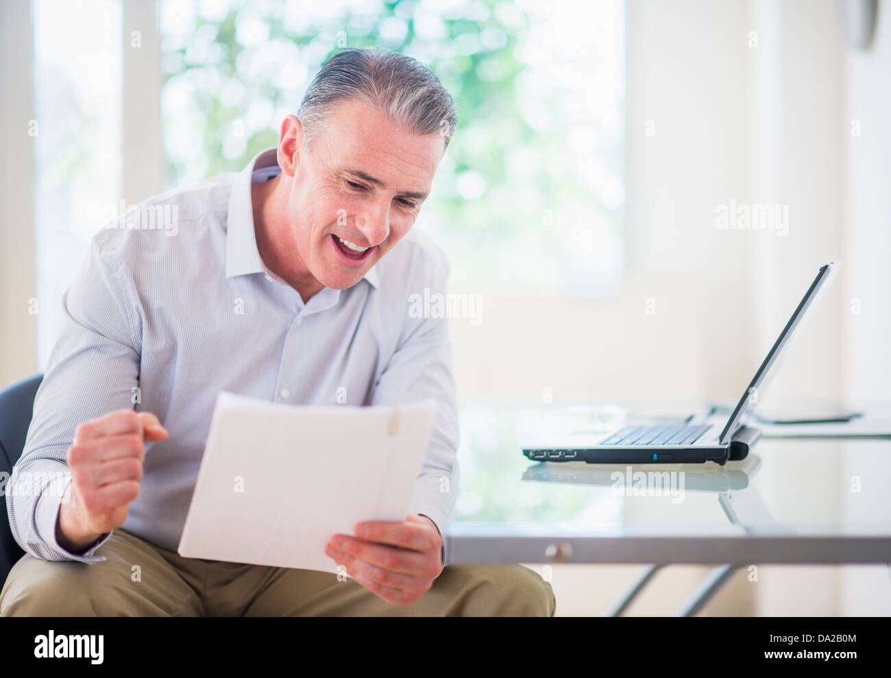 Portrait of man reading documents in office Stock Photo - Alamy