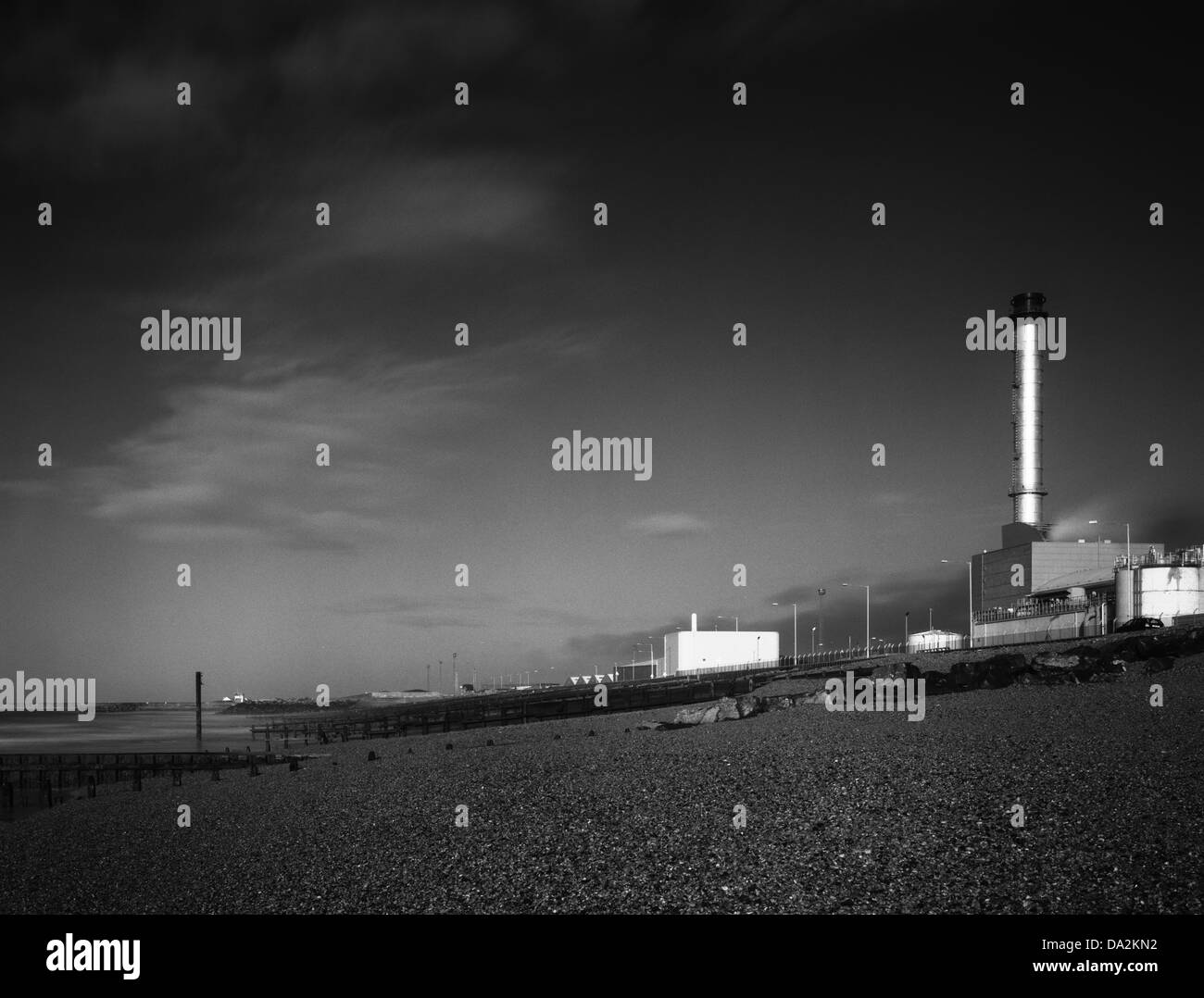 Power station and chimney against dark sky from beach,black and white ...