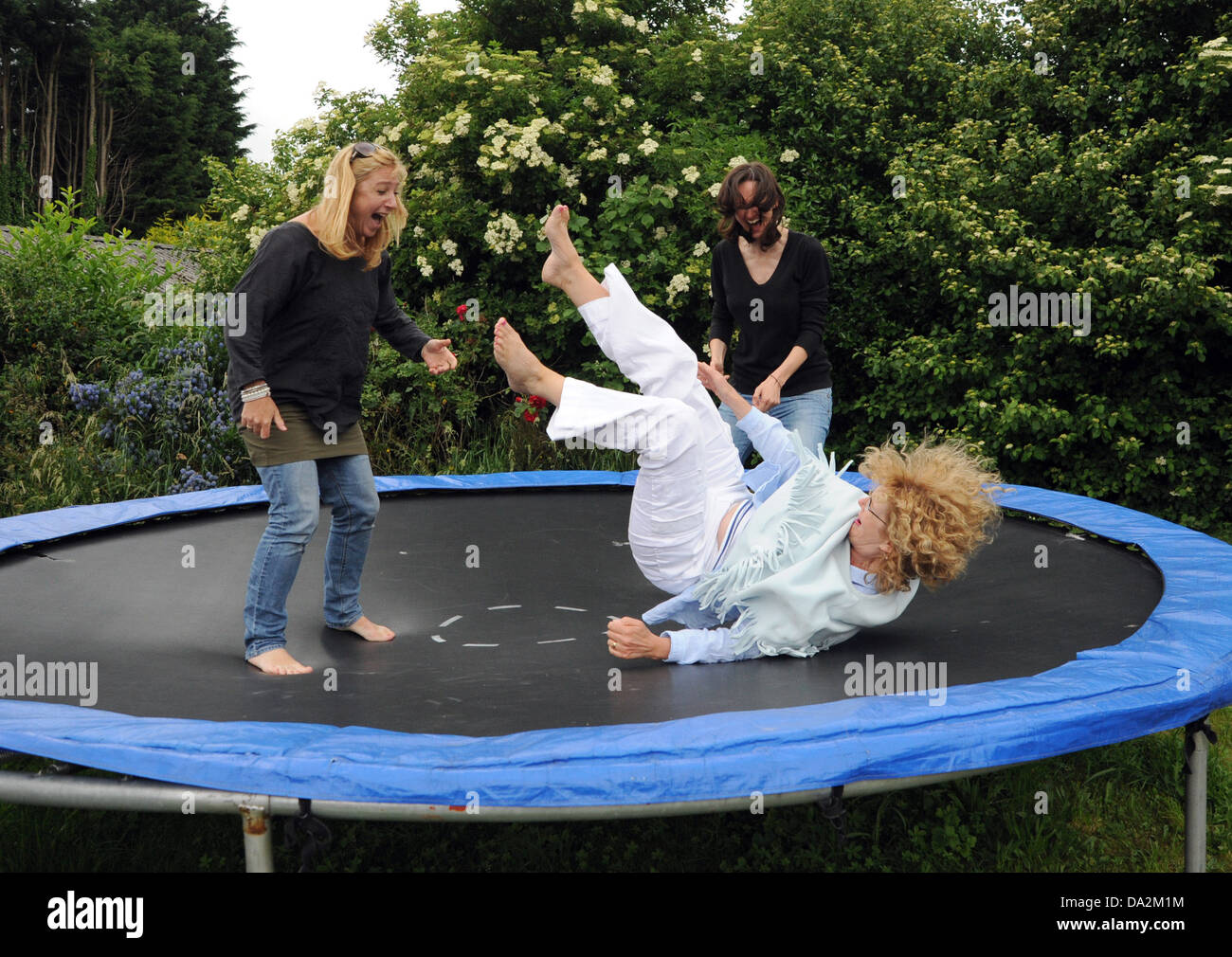 Female adults having fun bouncing on a trampoline in the garden Stock ...