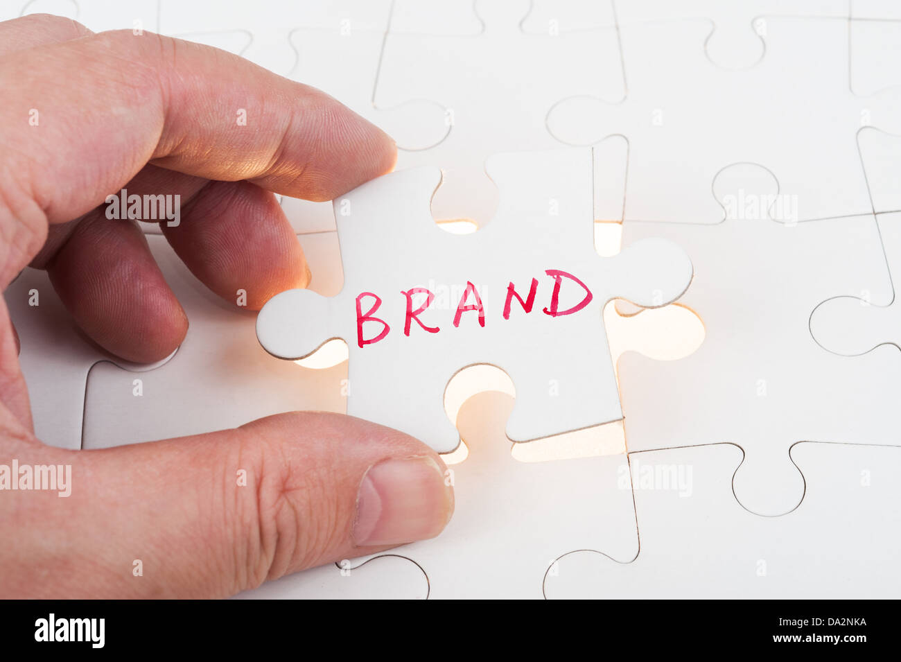 Hand holding puzzle piece which written brand word and inserting it ...