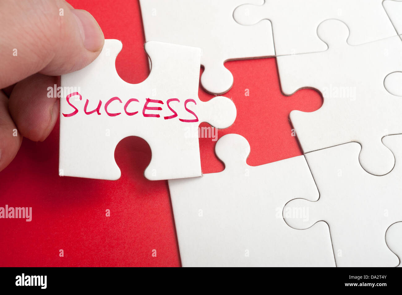 Hand holding puzzle piece which written success word and inserting it ...