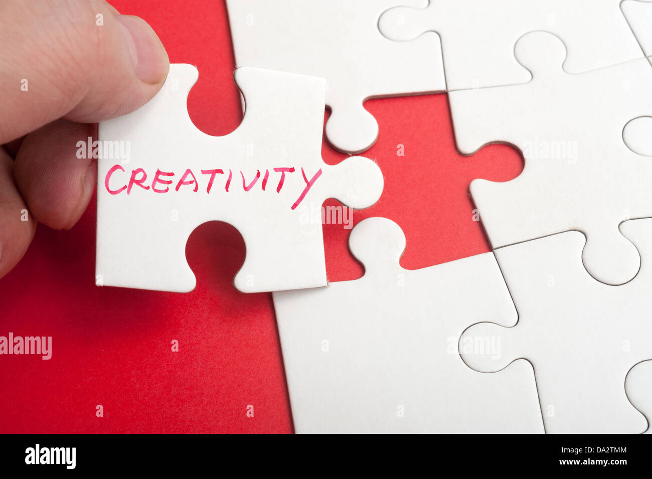 Hand holding puzzle piece which written creativity word and inserting ...