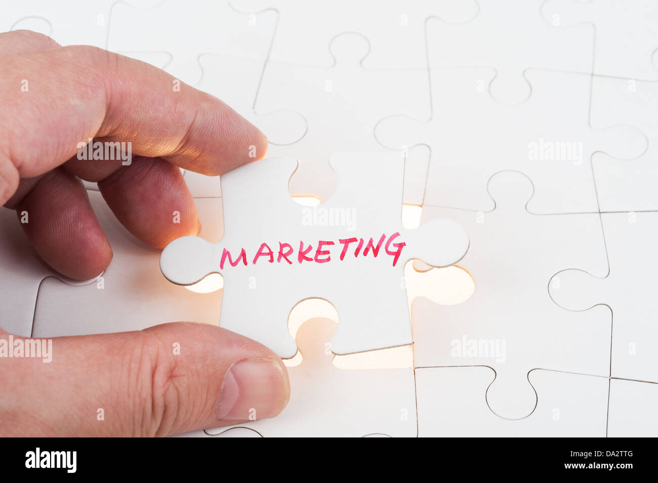 Hand holding puzzle piece which written marketing word and inserting it ...