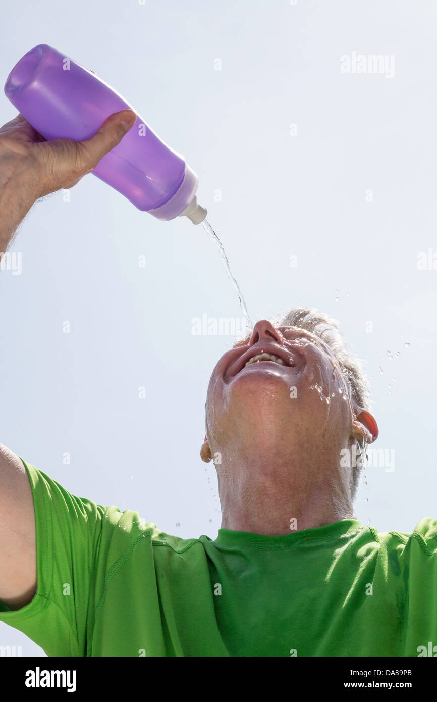 Senior man pouring water over his face to relieve heat exhaustion ...