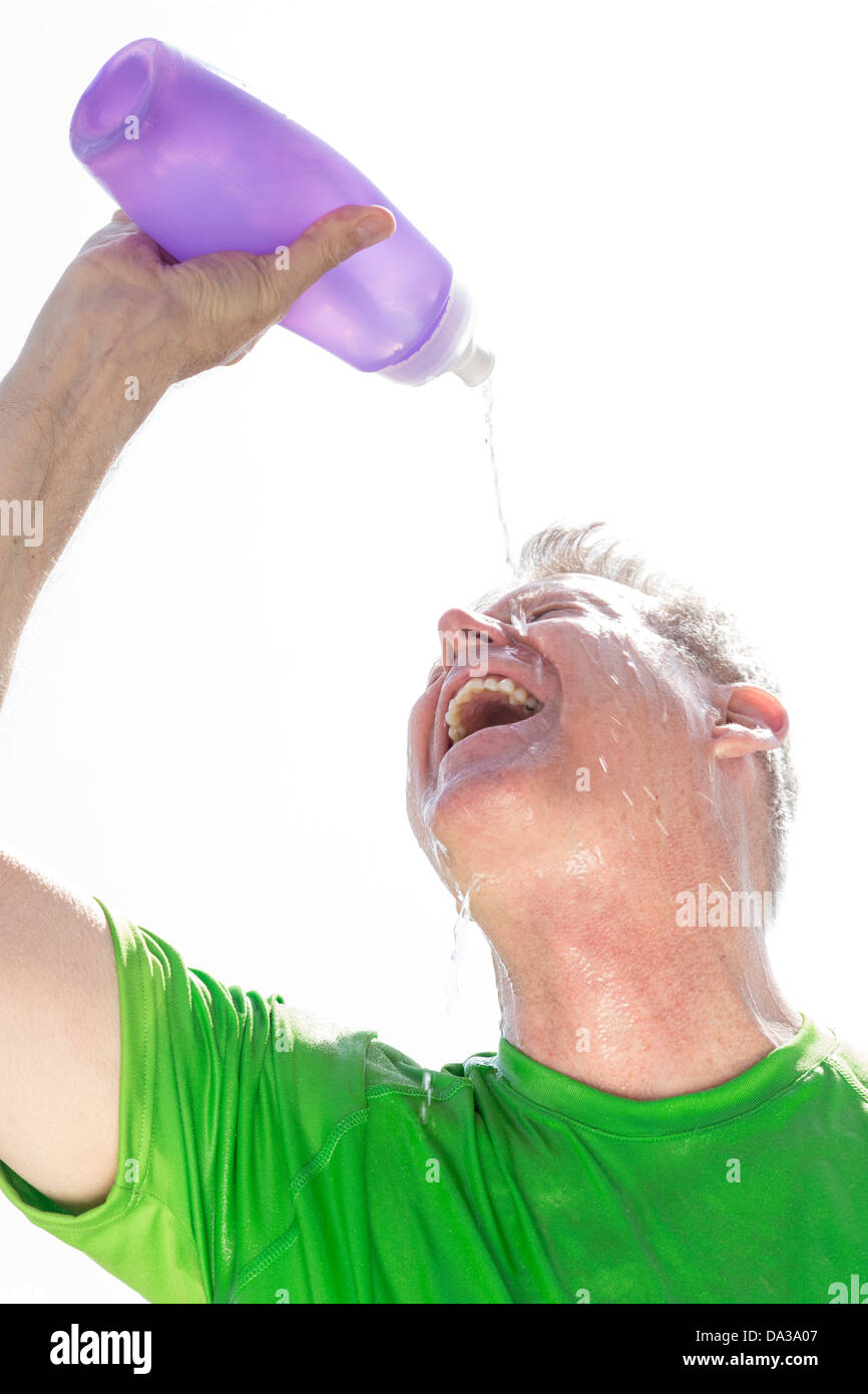Senior man pouring water over his face to relieve heat exhaustion ...