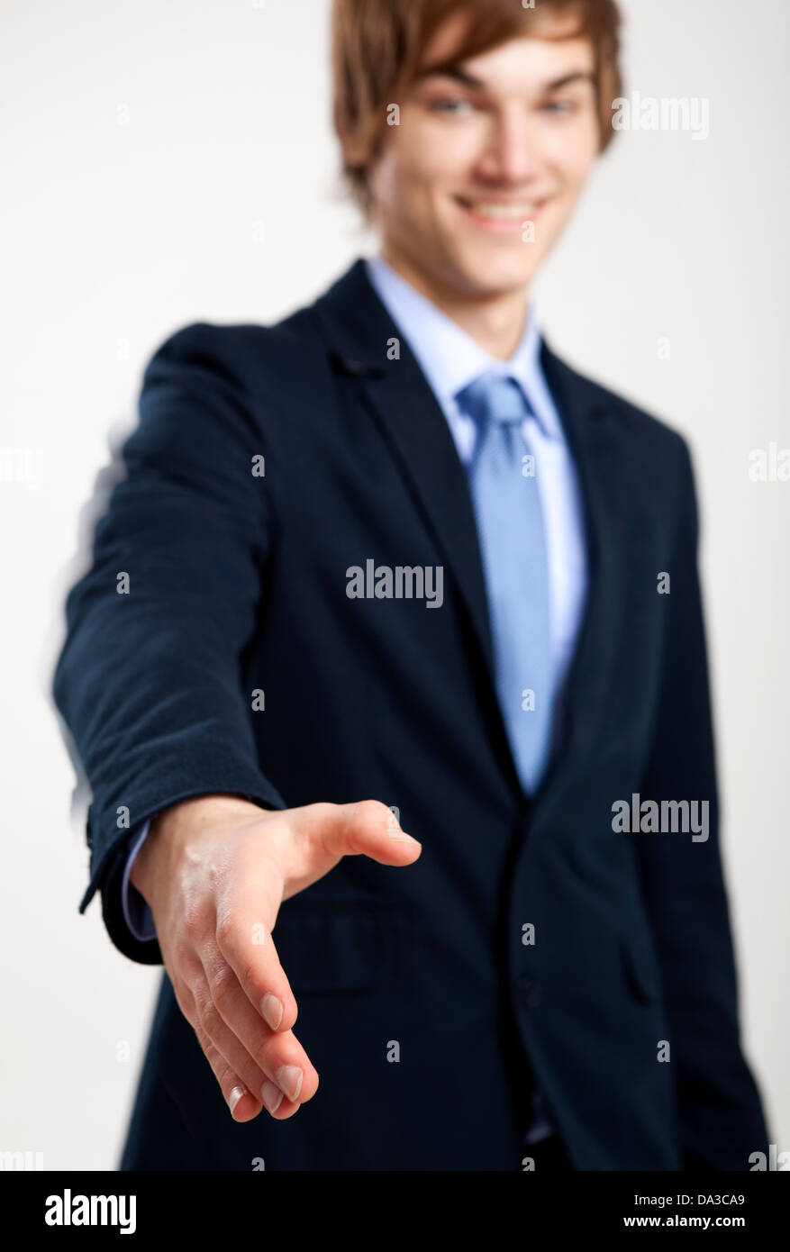 Young businessman giving a hand shake, over a gray background Stock ...