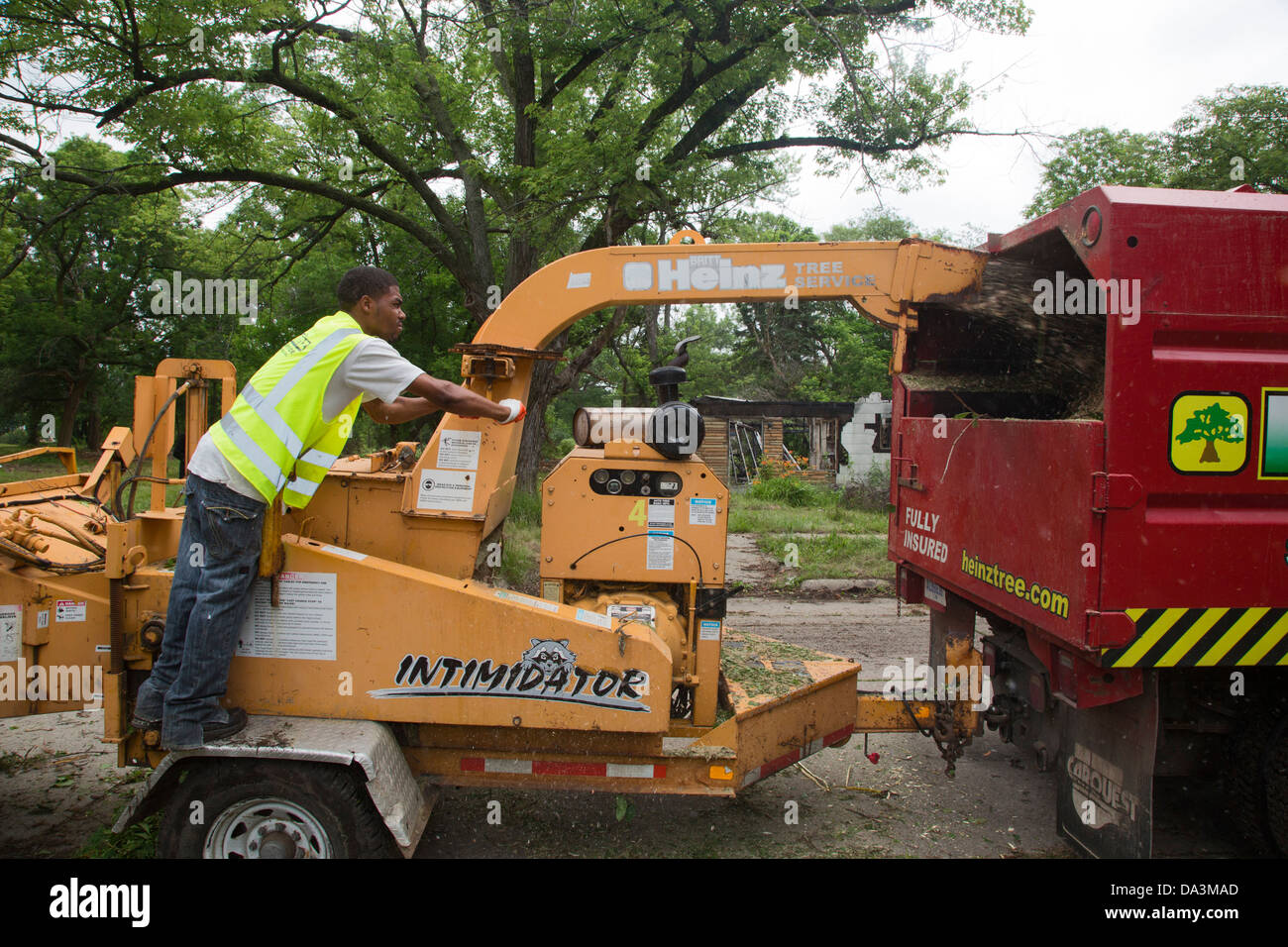 Workers feed bush and small trees into a chipper as the Detroit Blight ...