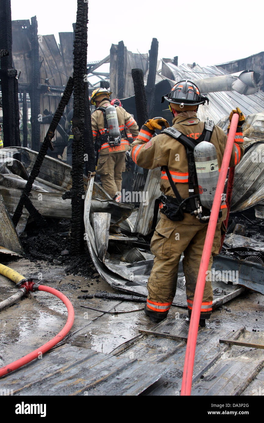 A firefighter pulling a hoseline into a collapsed building site Stock ...