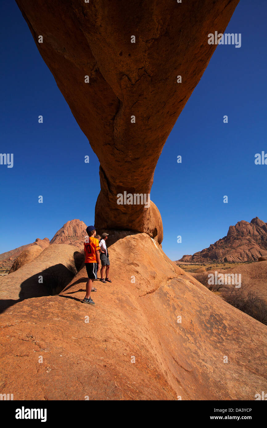 Family under natural rock arch at Spitzkoppe (left), and Pondok Mountains in distance (right ...