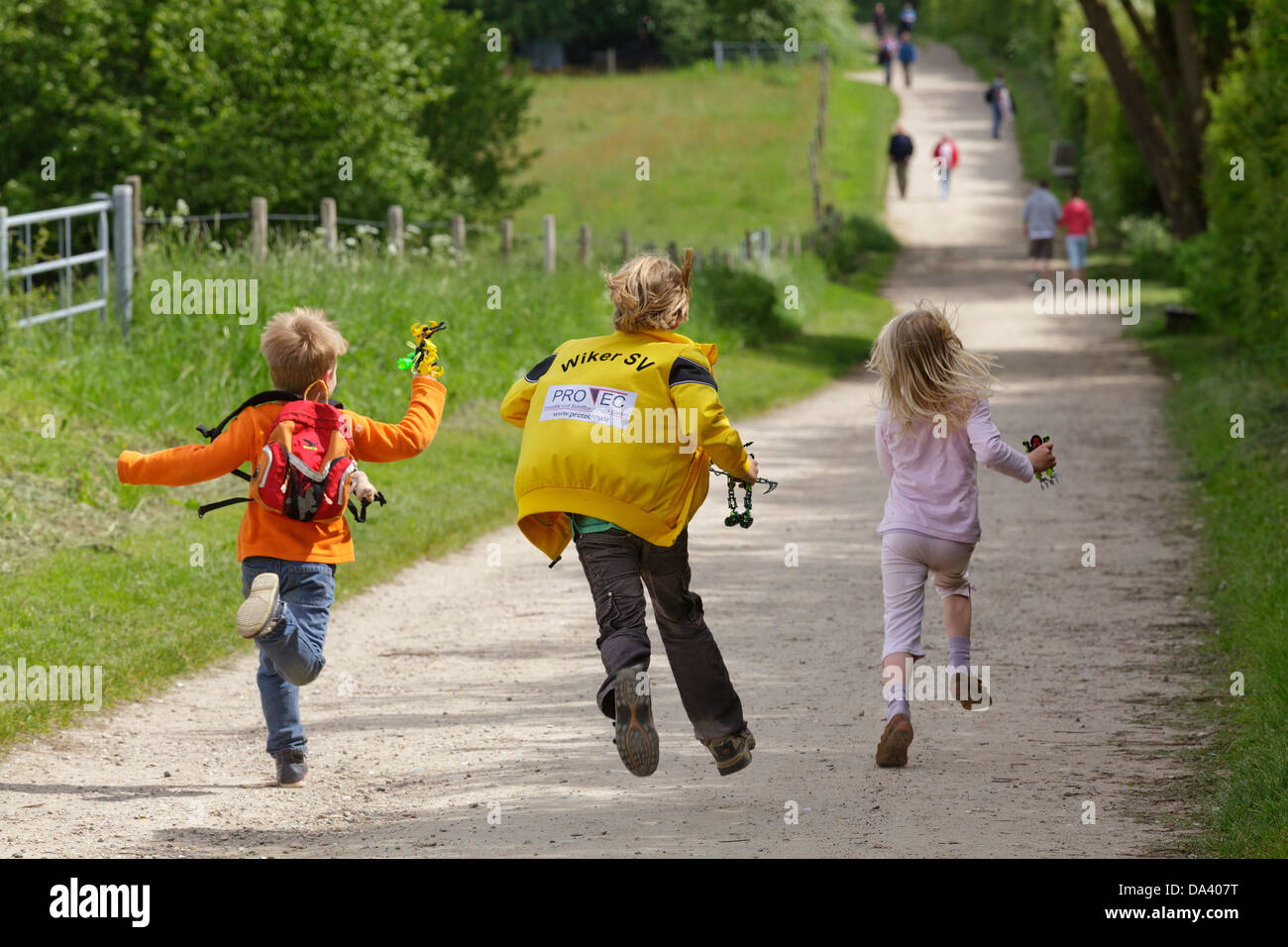 three children running along a path Stock Photo - Alamy