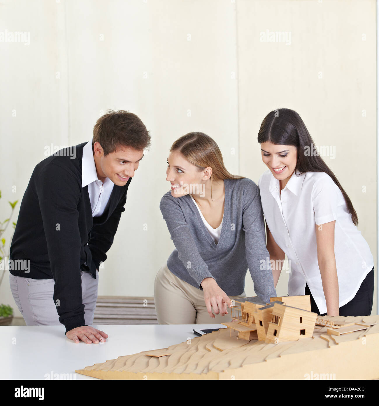 Three architecture students discussing 3D building model on desk Stock ...