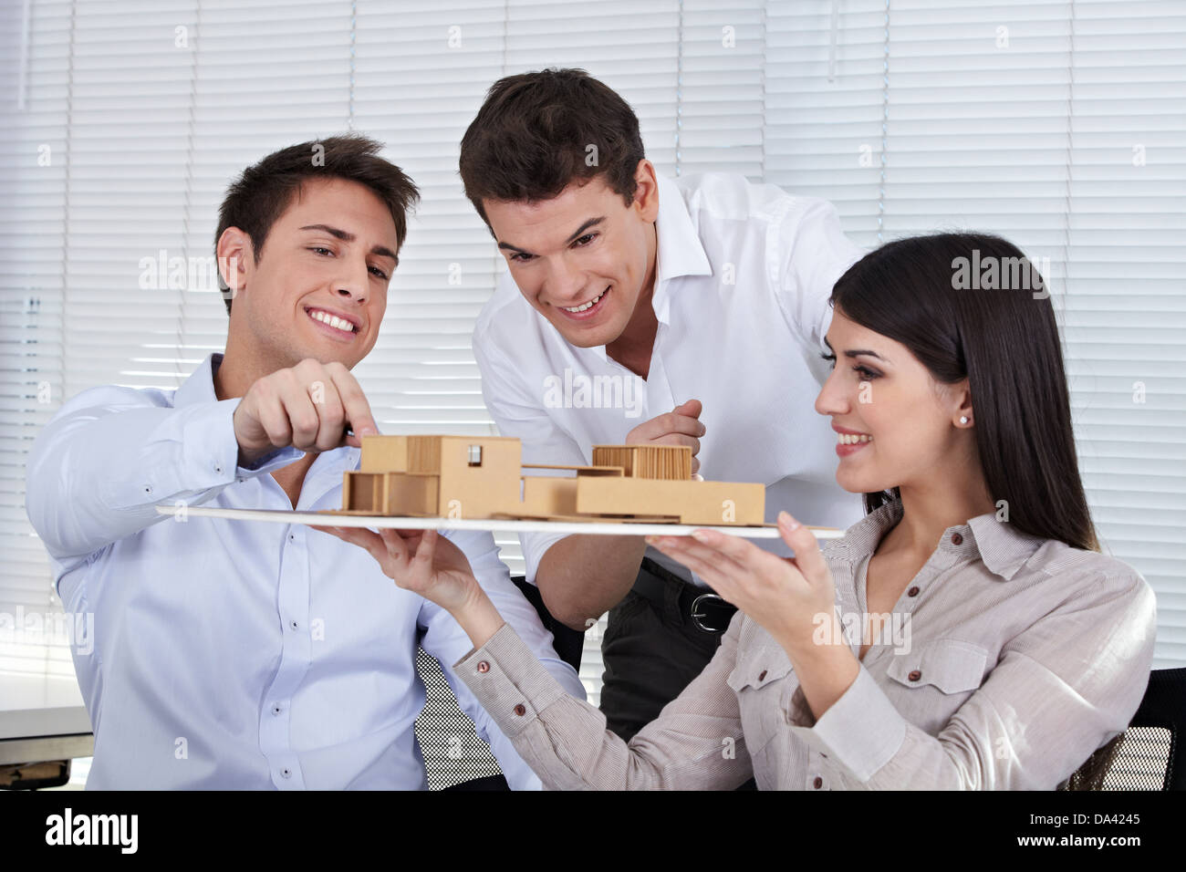 Three architects in their office discussing a building model Stock ...