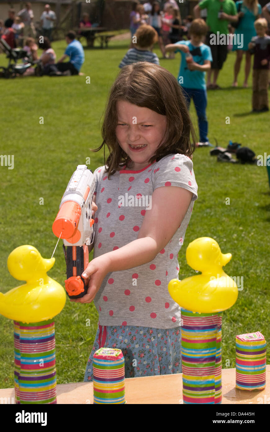 7 Year Old Girl At Summer Fete Using Water Pistol To Squirt Plastic Ducks Sheet Hampshire Uk