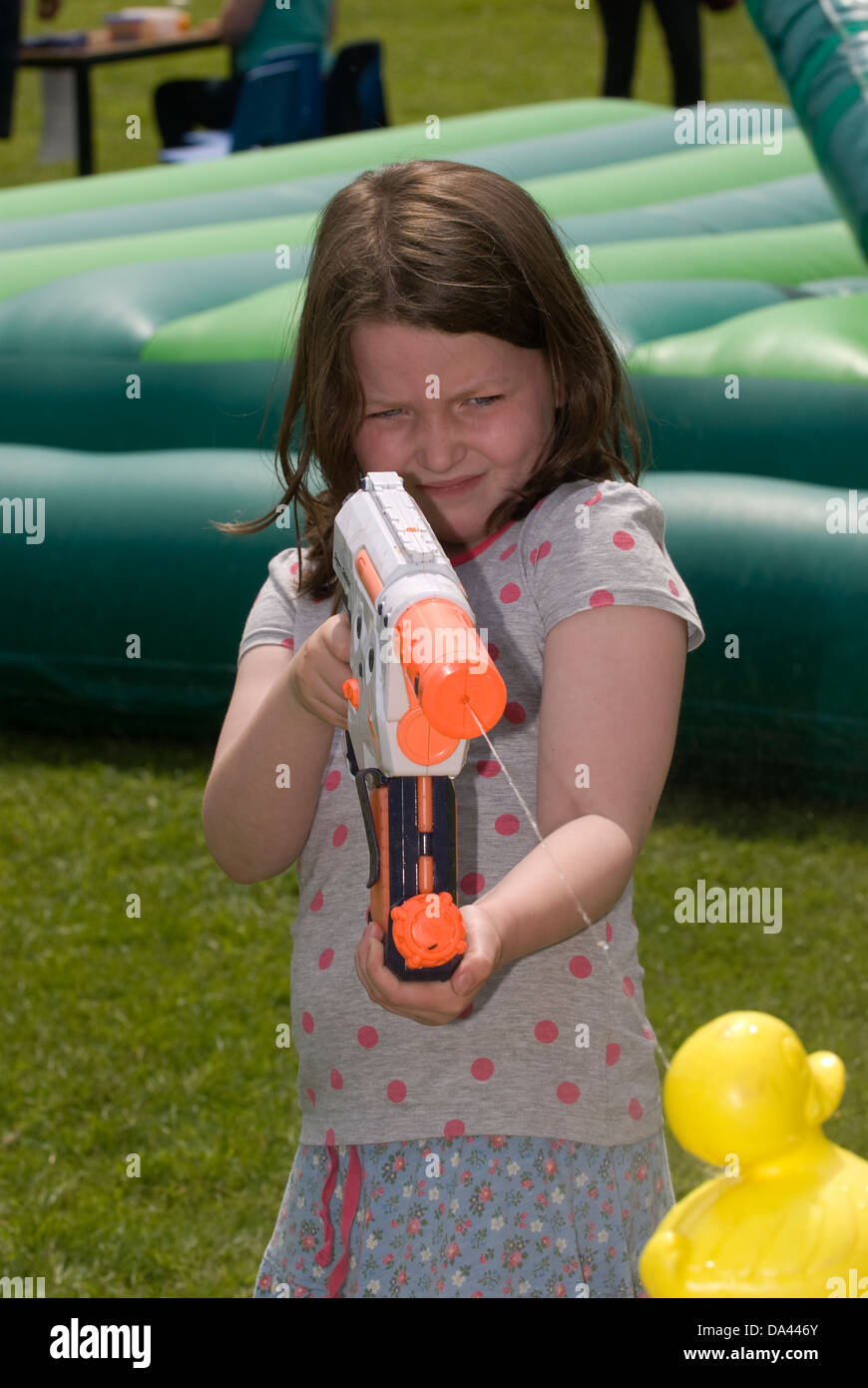 7 Year Old Girl At Summer Fete Using Water Pistol To Squirt Plastic Ducks Sheet Hampshire Uk