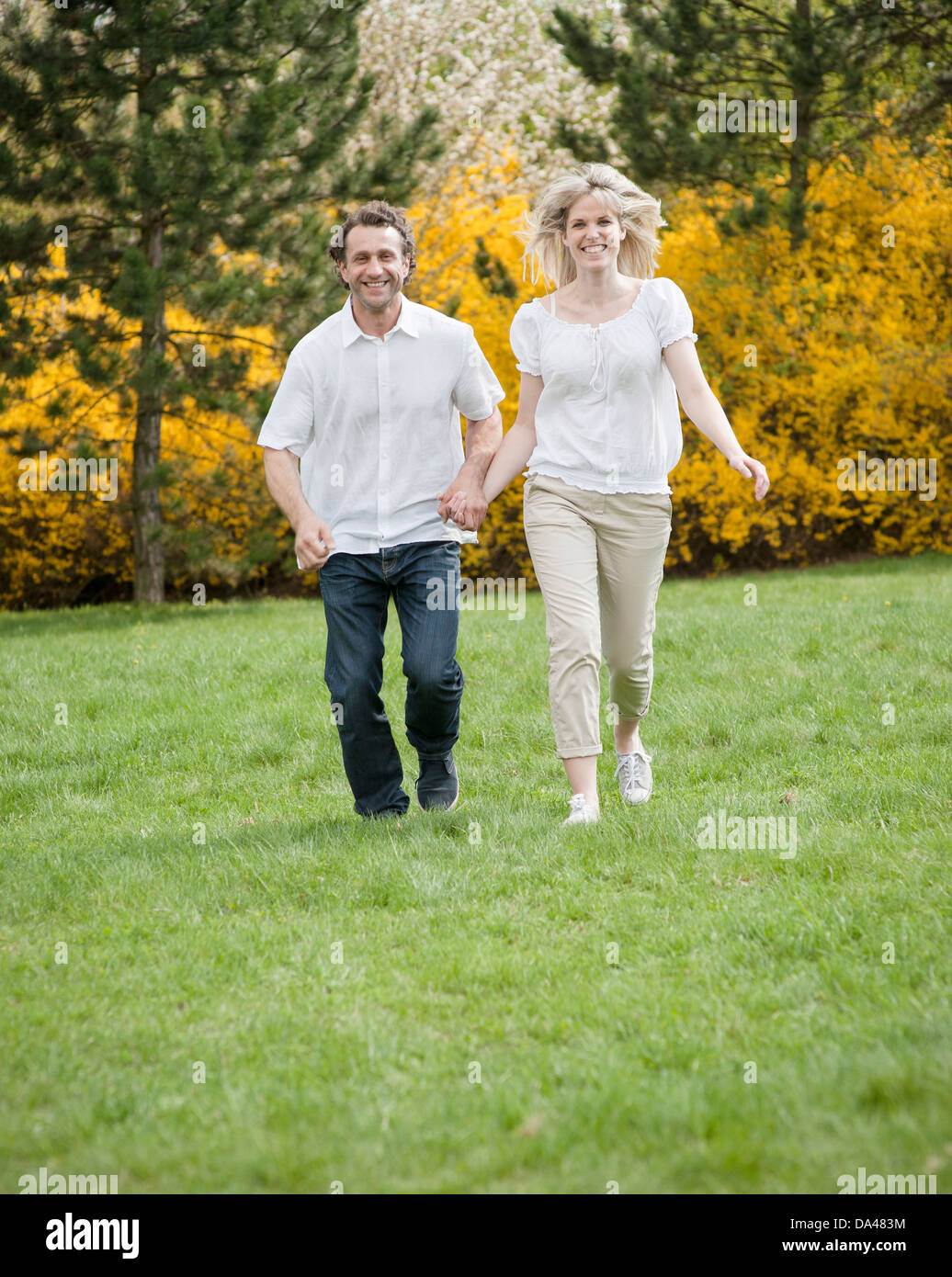 Couple running through park holding hands Stock Photo - Alamy