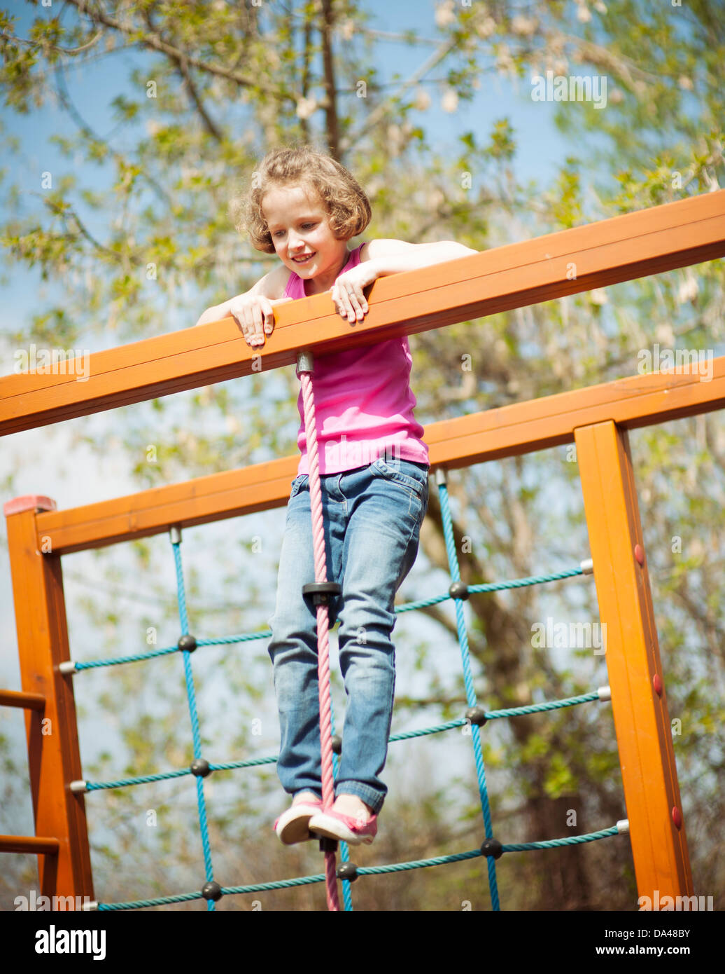 Young girl standing at top of rope and climbing frame Stock Photo - Alamy