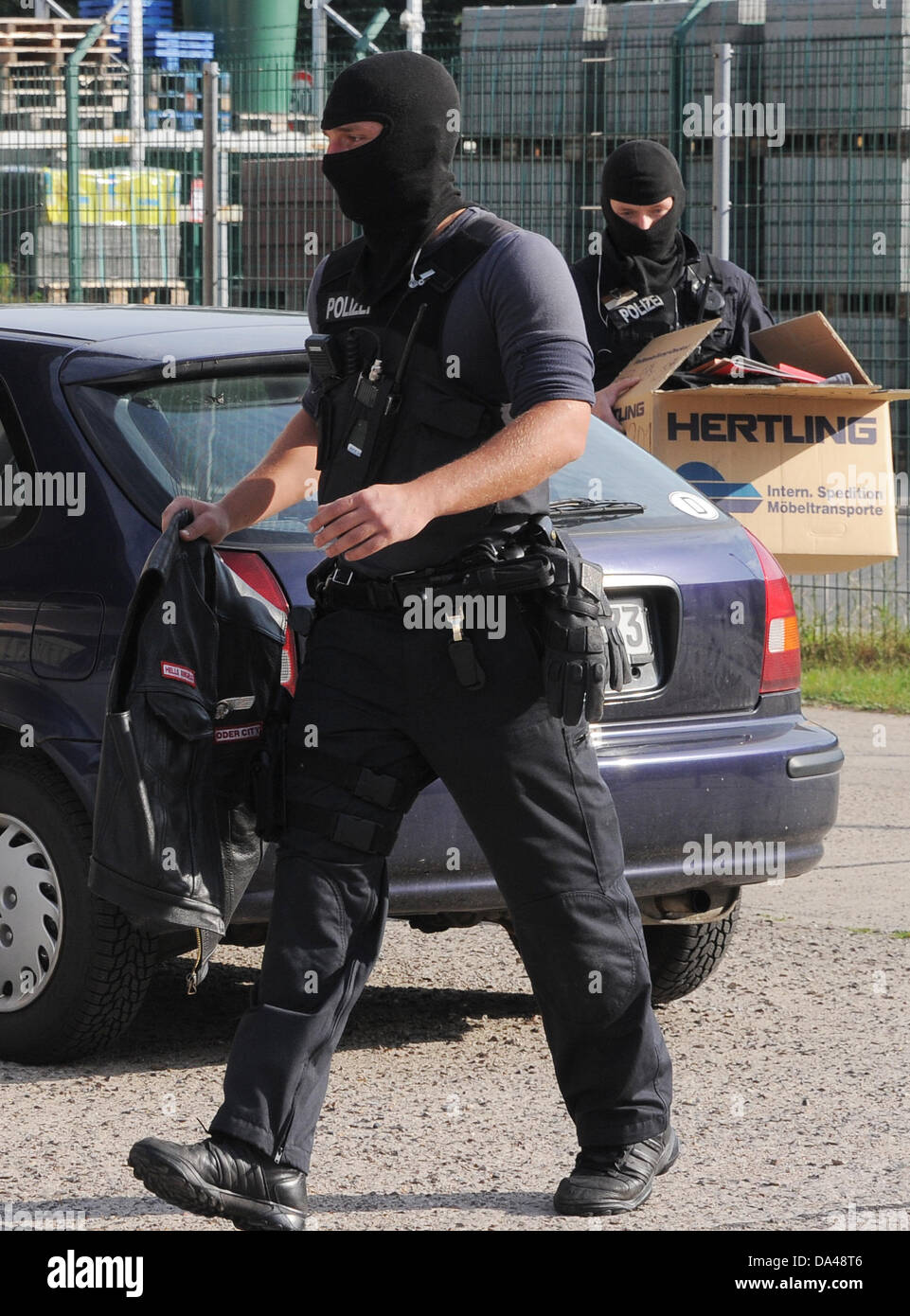 Police officers carry boxes of confiscated objects to a car in ...