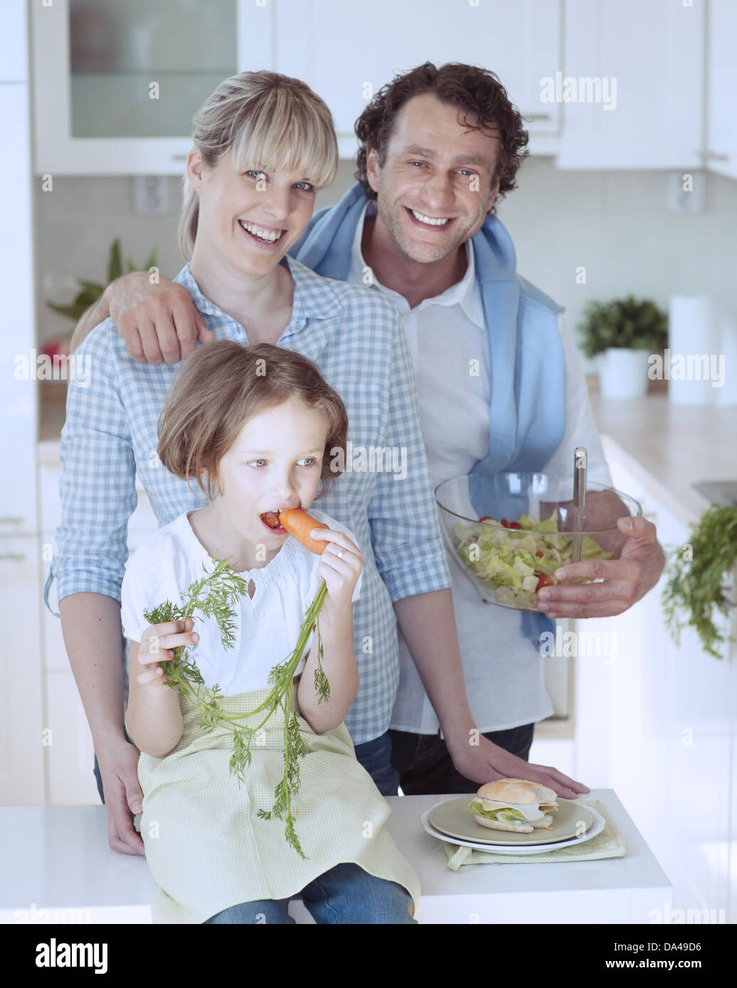 Young girl eating carrot with parents Stock Photo - Alamy