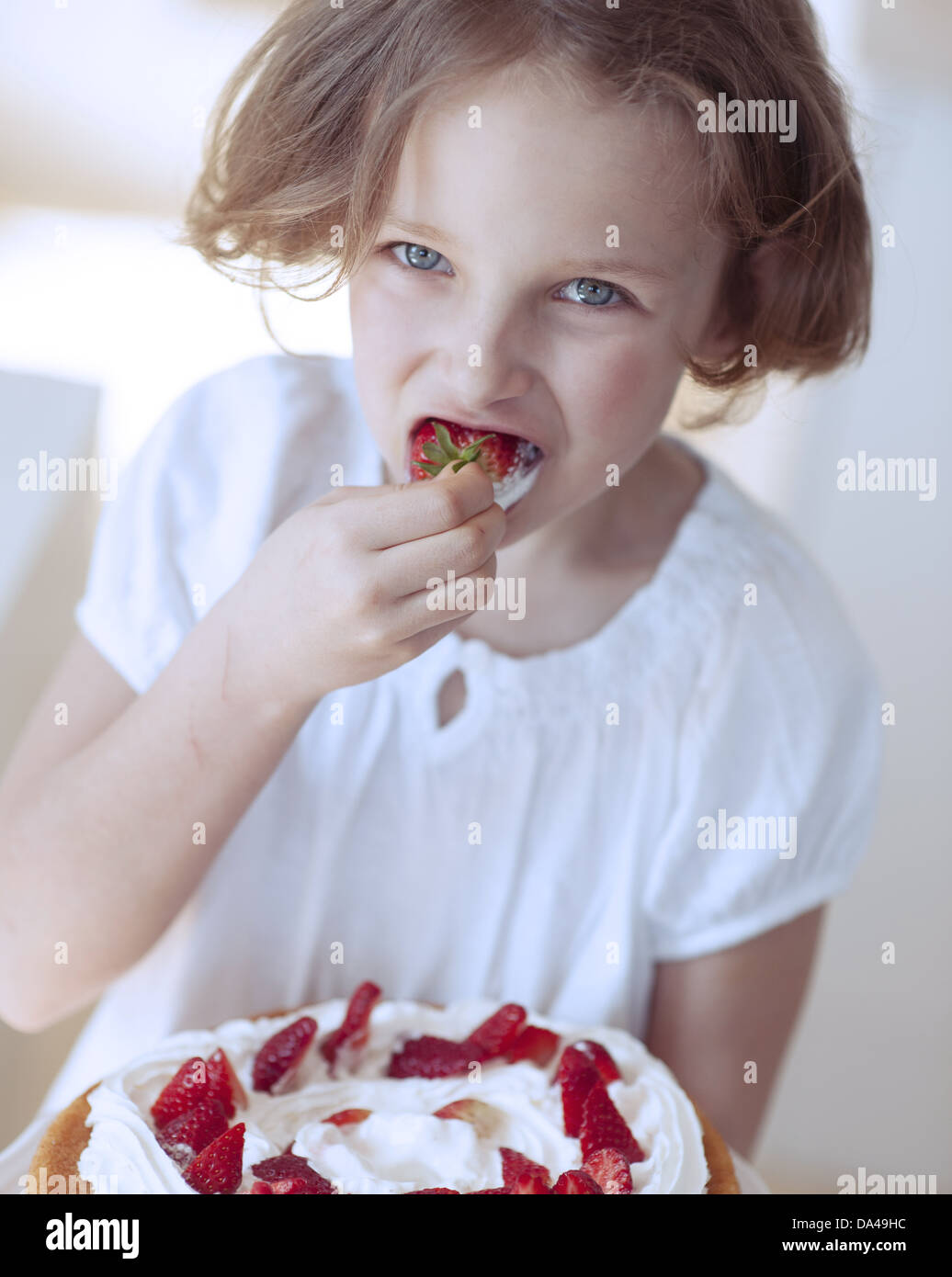 Close-up of Young girl with cake eating strawberry Stock Photo - Alamy