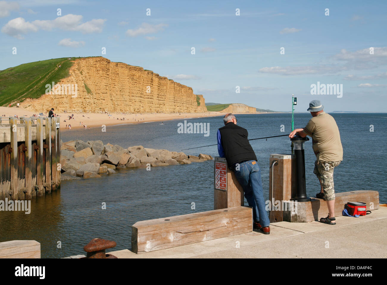 Fishing from pier East Cliff and beach West Bay Bridport Dorset England ...