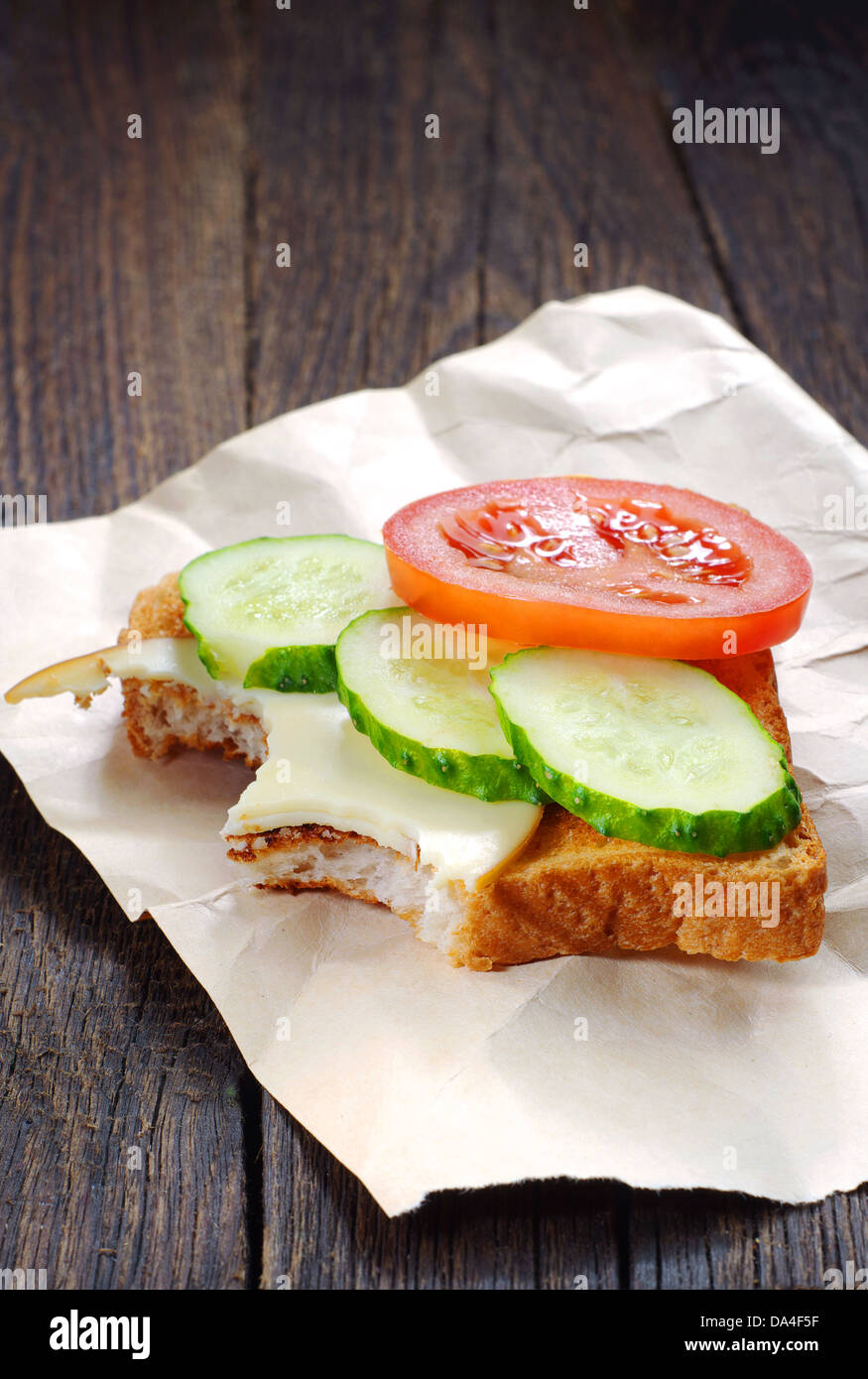 Bitten toast with cheese and vegetables on crumpled paper Stock Photo ...