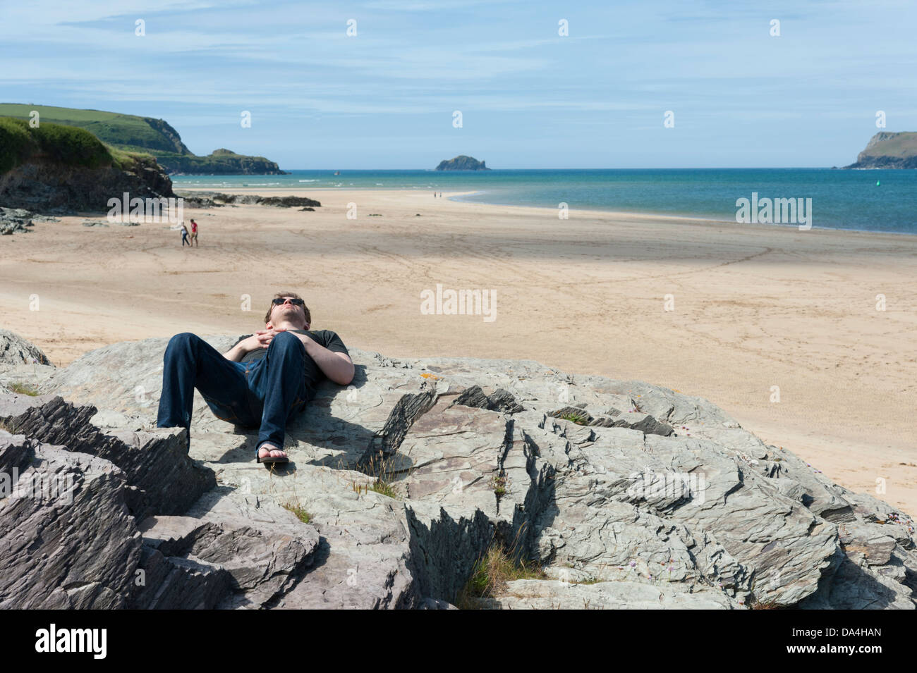 A man sunbathing on a rock on the beach at Padstow Cornwall UK on the ...