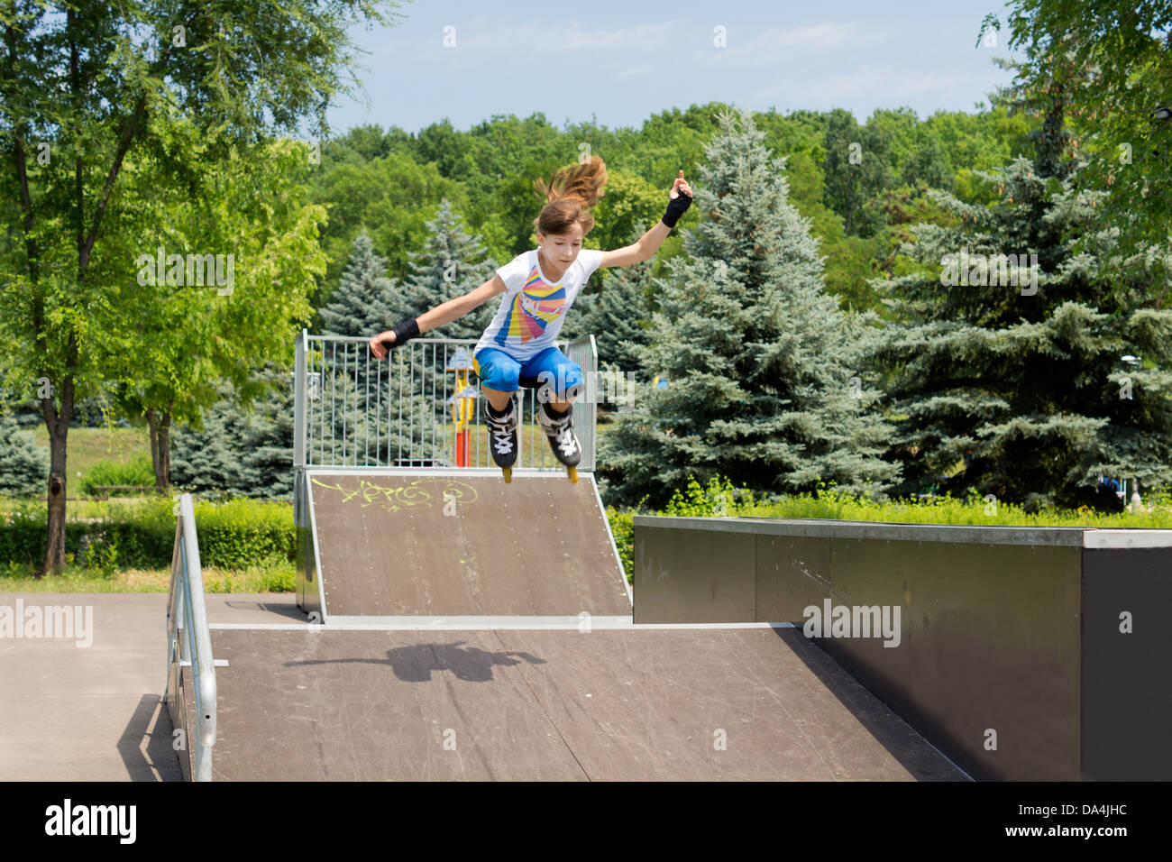 Agile young female roller skater jumping mid air as she travels down a ...