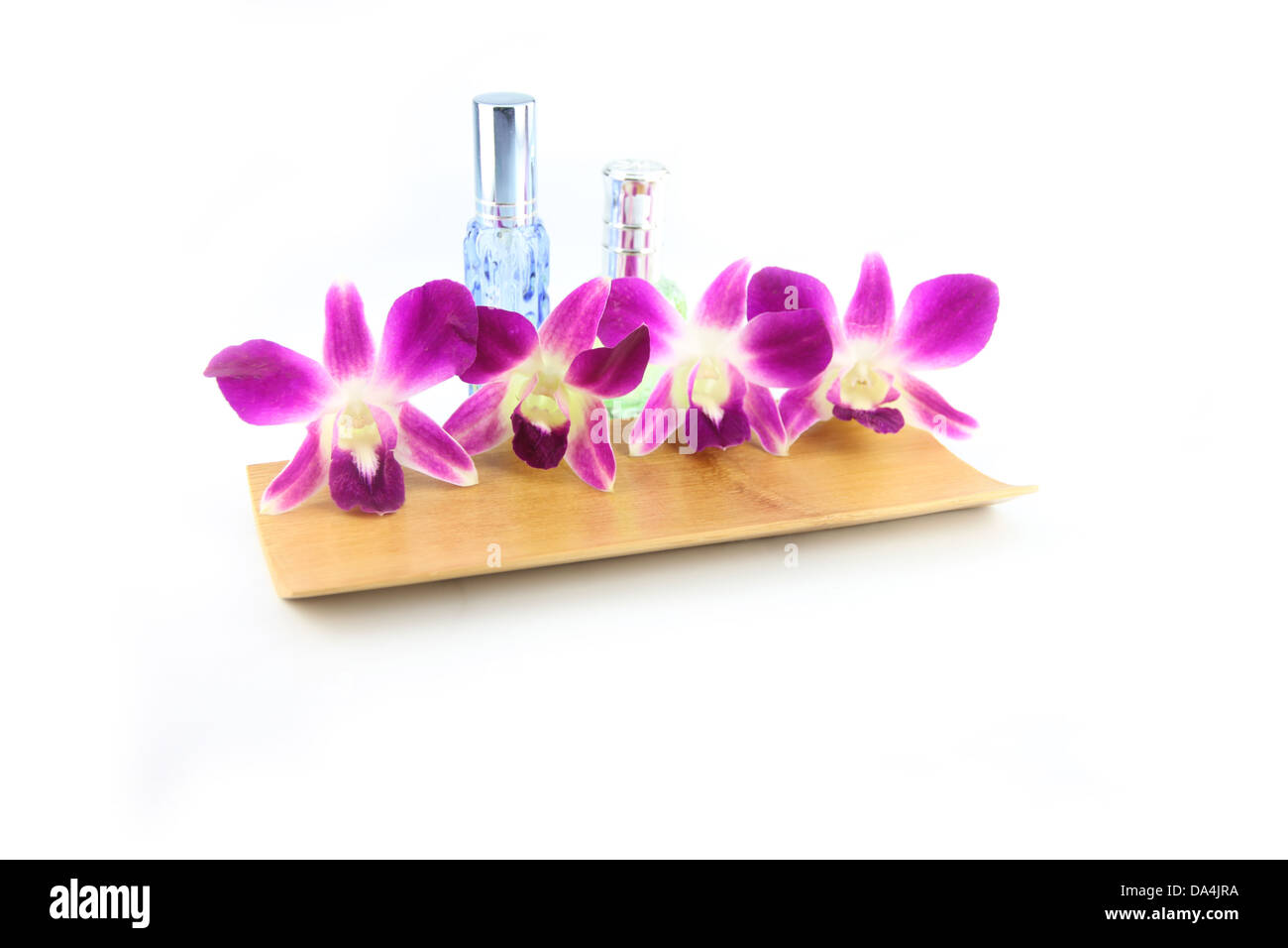 Purple orchid and perfume bottles in bamboo dish on white background ...