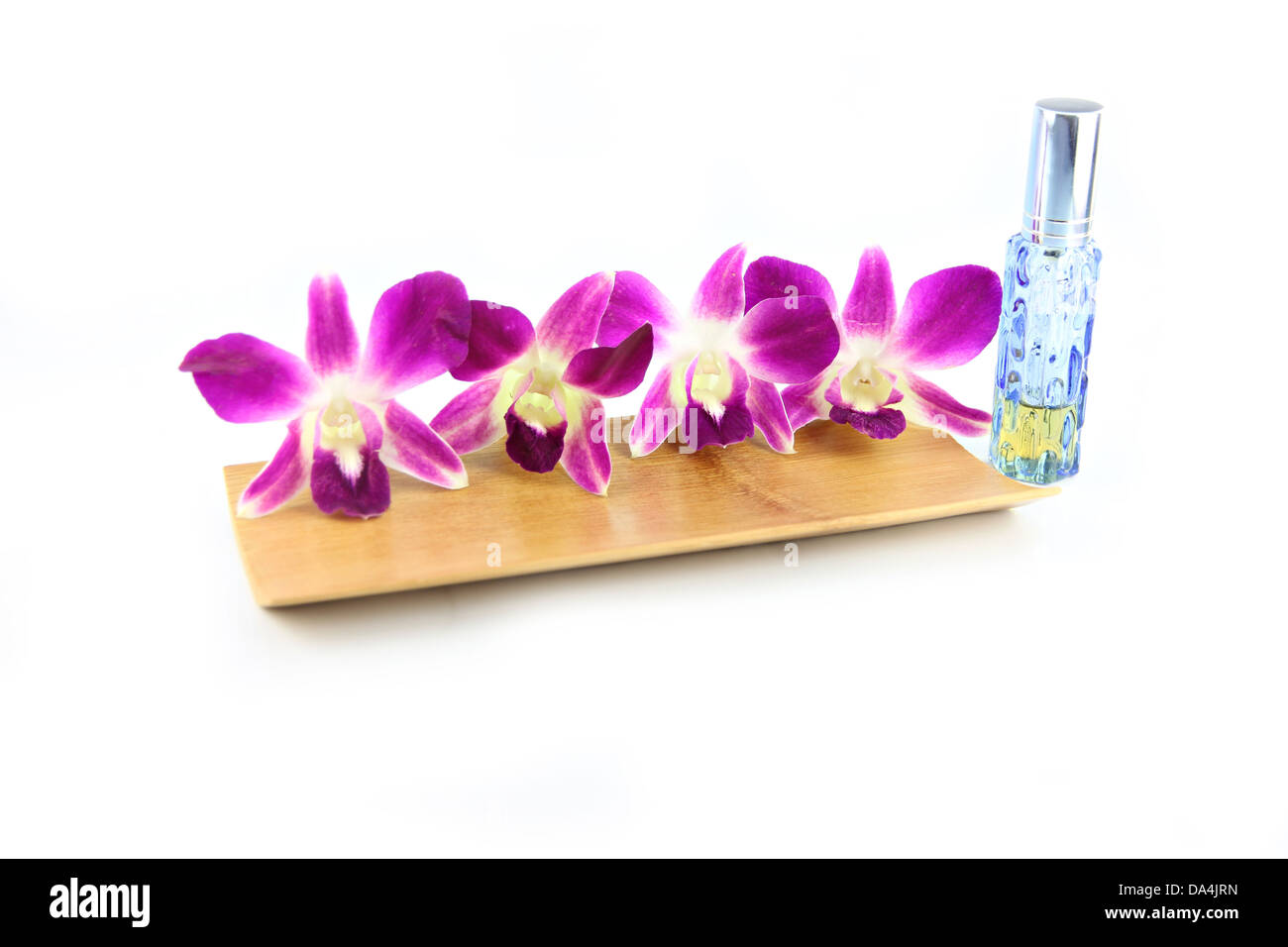 Purple orchid and perfume bottles in bamboo dish on white background ...