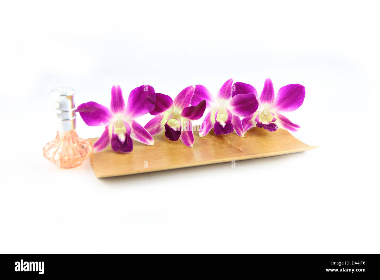 Purple orchid and perfume bottles in bamboo dish on white background ...