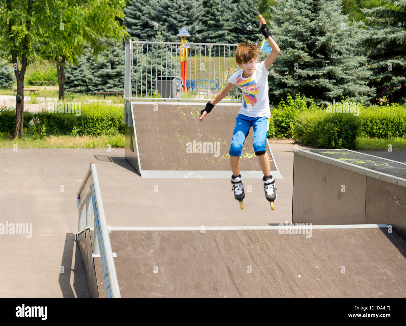 Young girl jumping in the air while roller skating as she skates down a ...