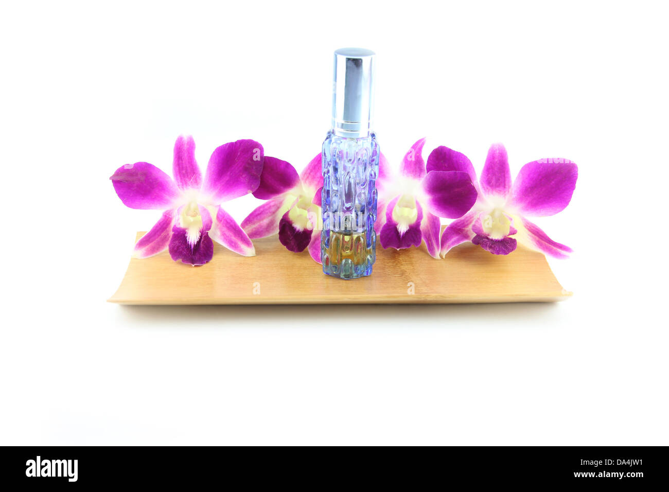 Purple orchid and perfume bottles in bamboo dish on white background ...