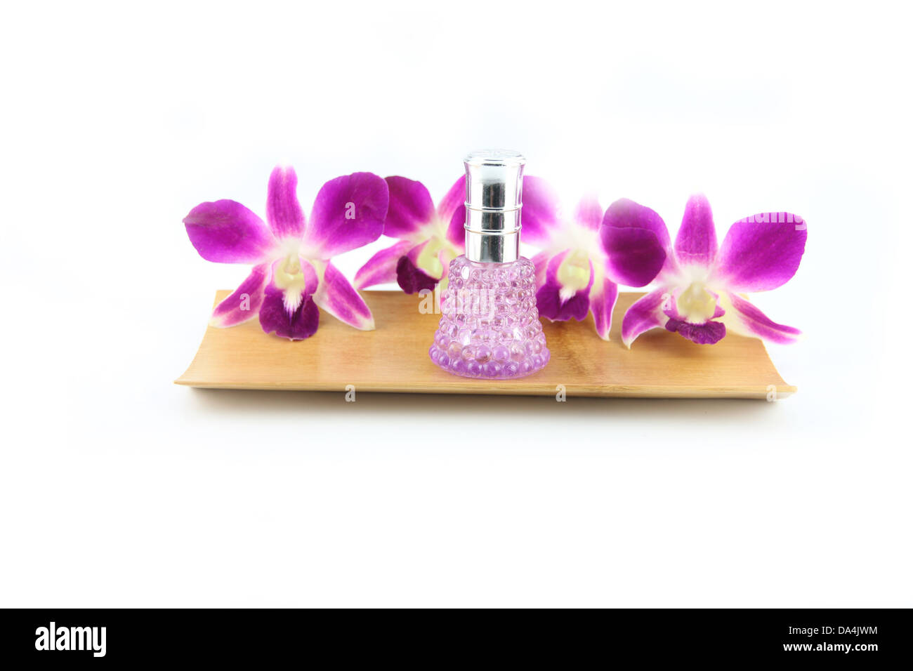 Purple orchid and perfume bottles in bamboo dish on white background ...