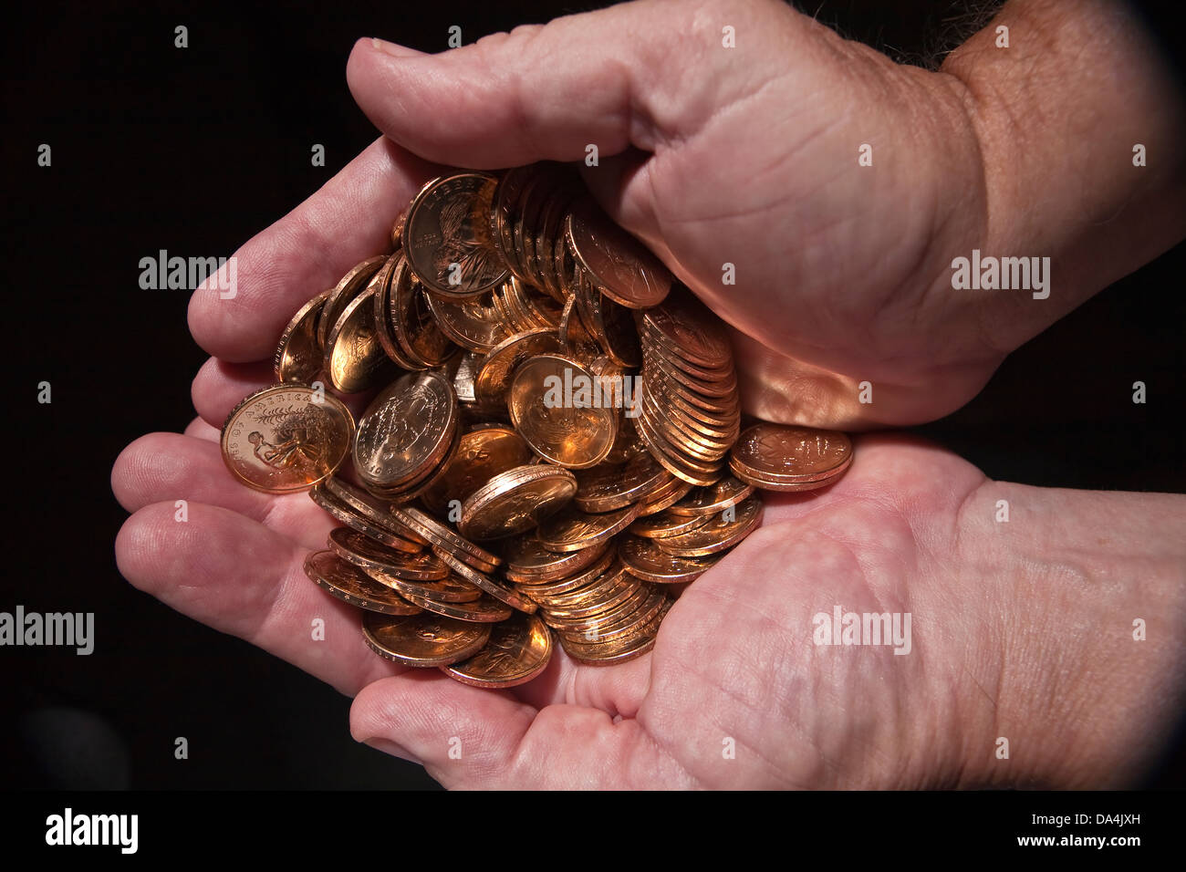 Older man's hands holding dollar gold coins with native american ...