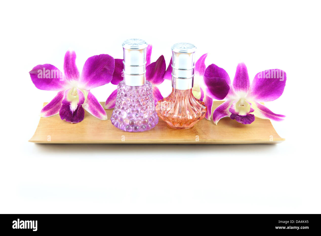 Purple orchid and perfume bottles in bamboo dish on white background ...