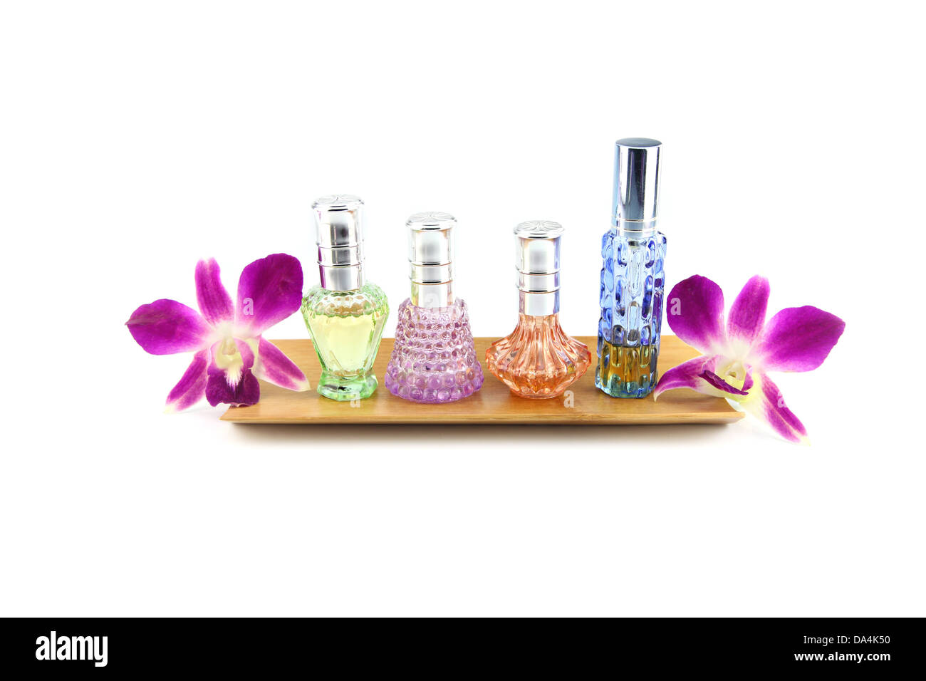 Purple orchid and perfume bottles in bamboo dish on white background ...
