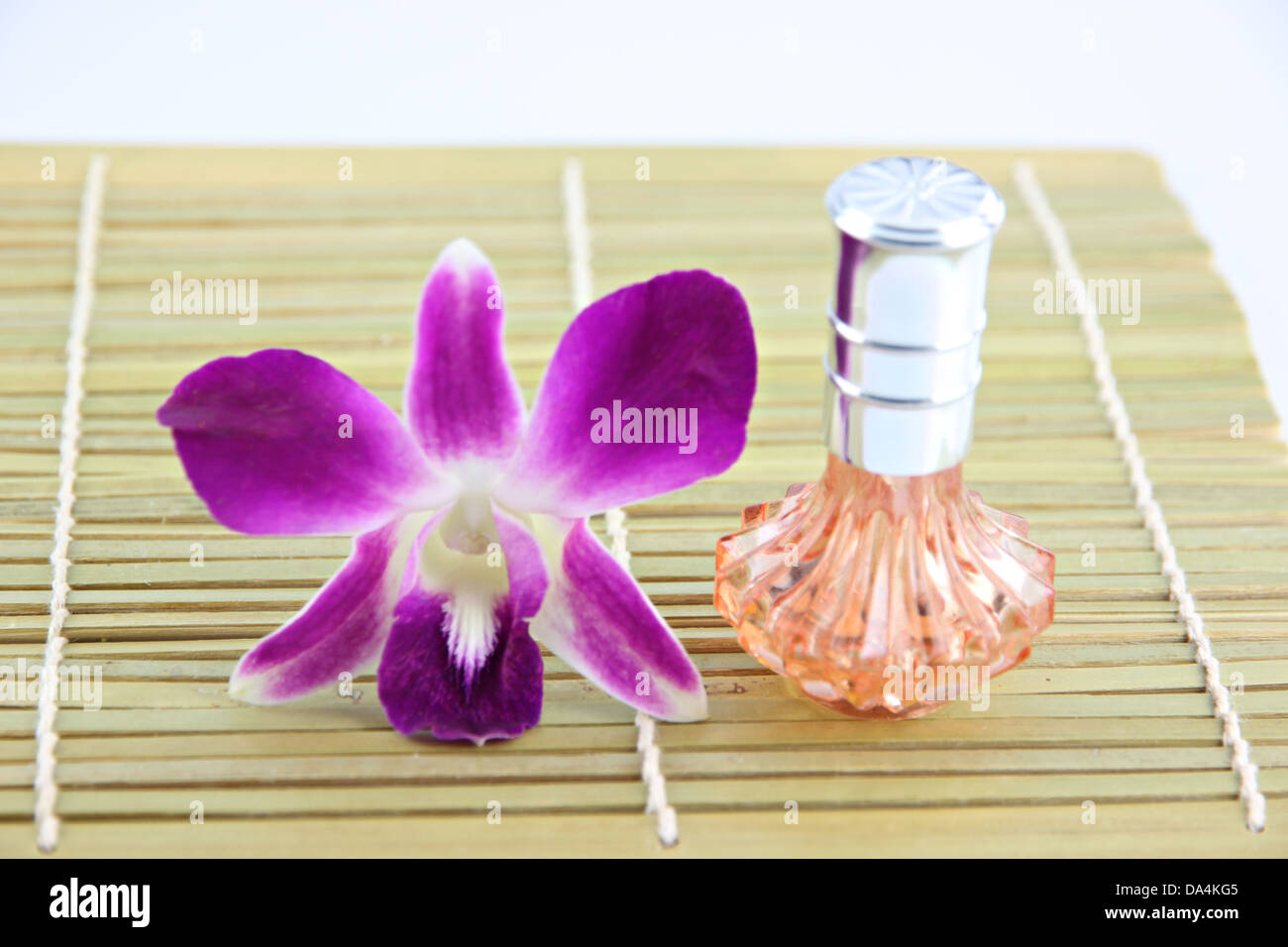 Purple orchid and Orange perfume bottles in bamboo dish on white ...