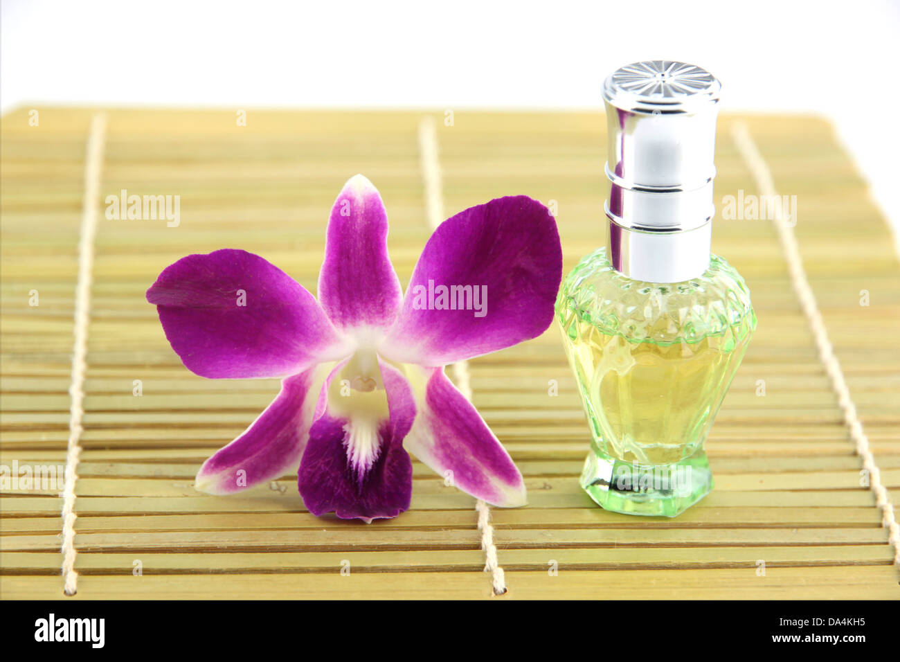 Purple orchid and Green perfume bottles in bamboo dish on white ...