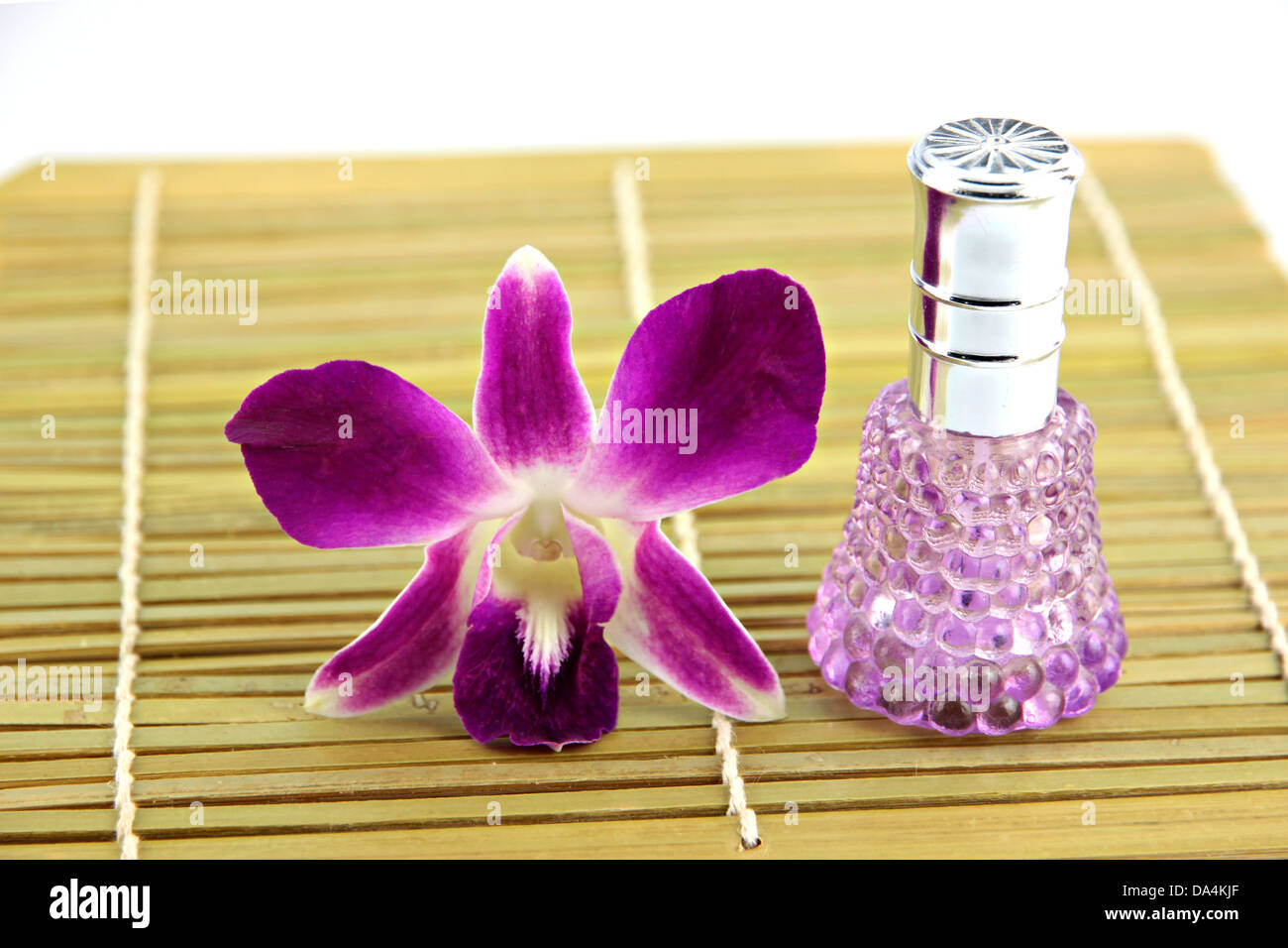 Purple orchid and perfume bottles in bamboo dish on white background ...