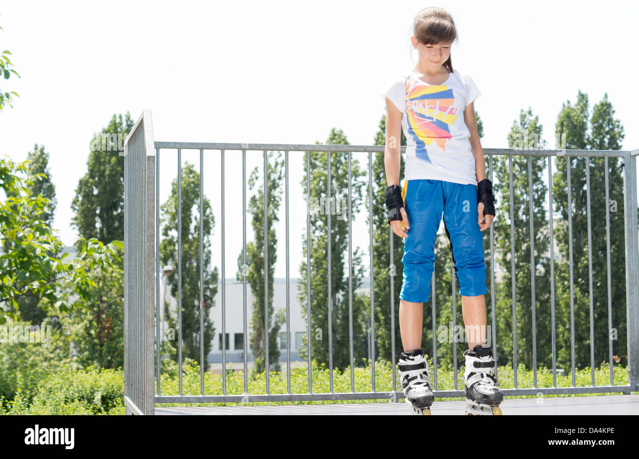 Young girl roller skater on top of a cement ramp at a skate park ...