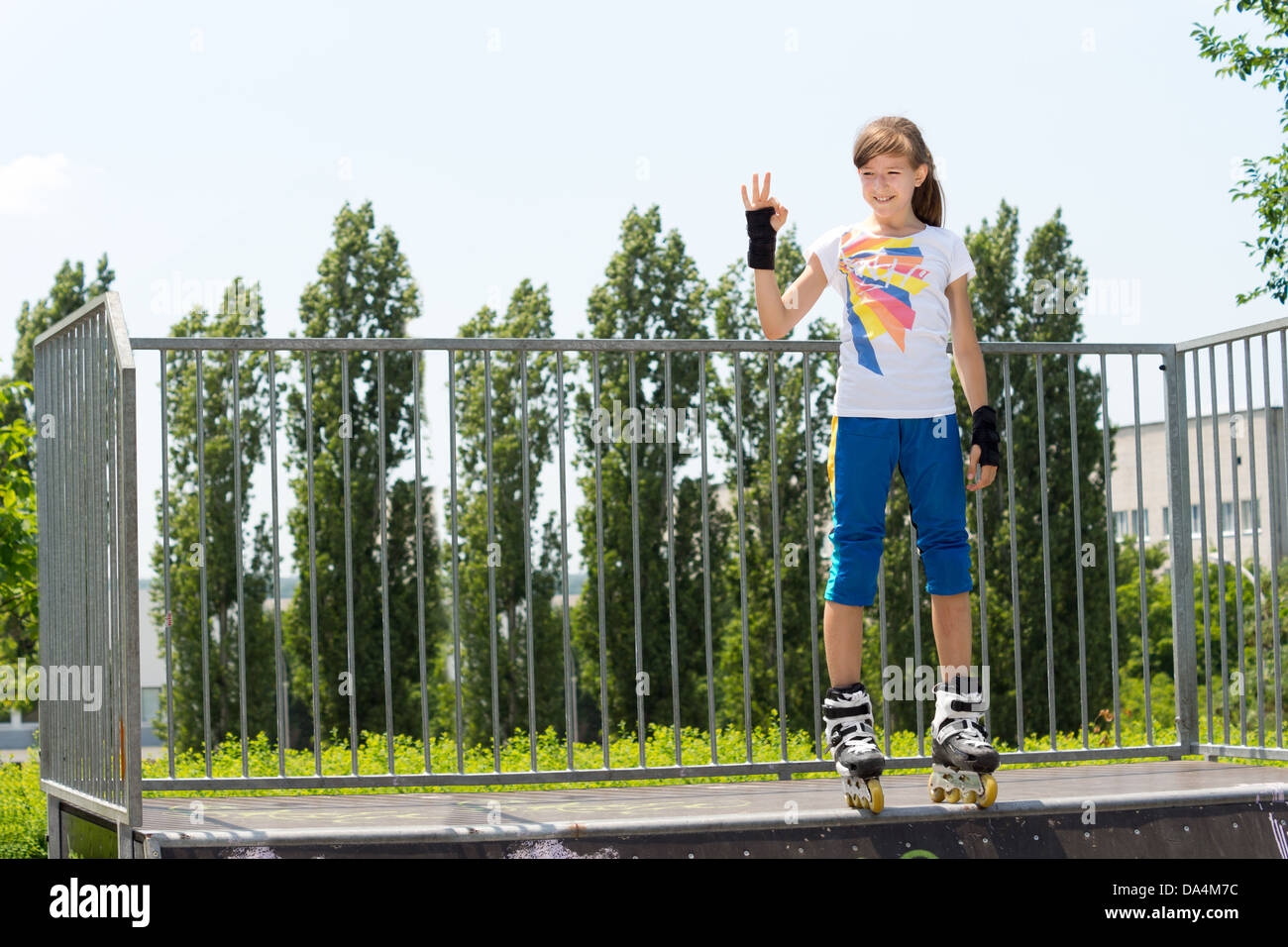 Young teenage girl roller skater standing at the top of a cement ramp ...