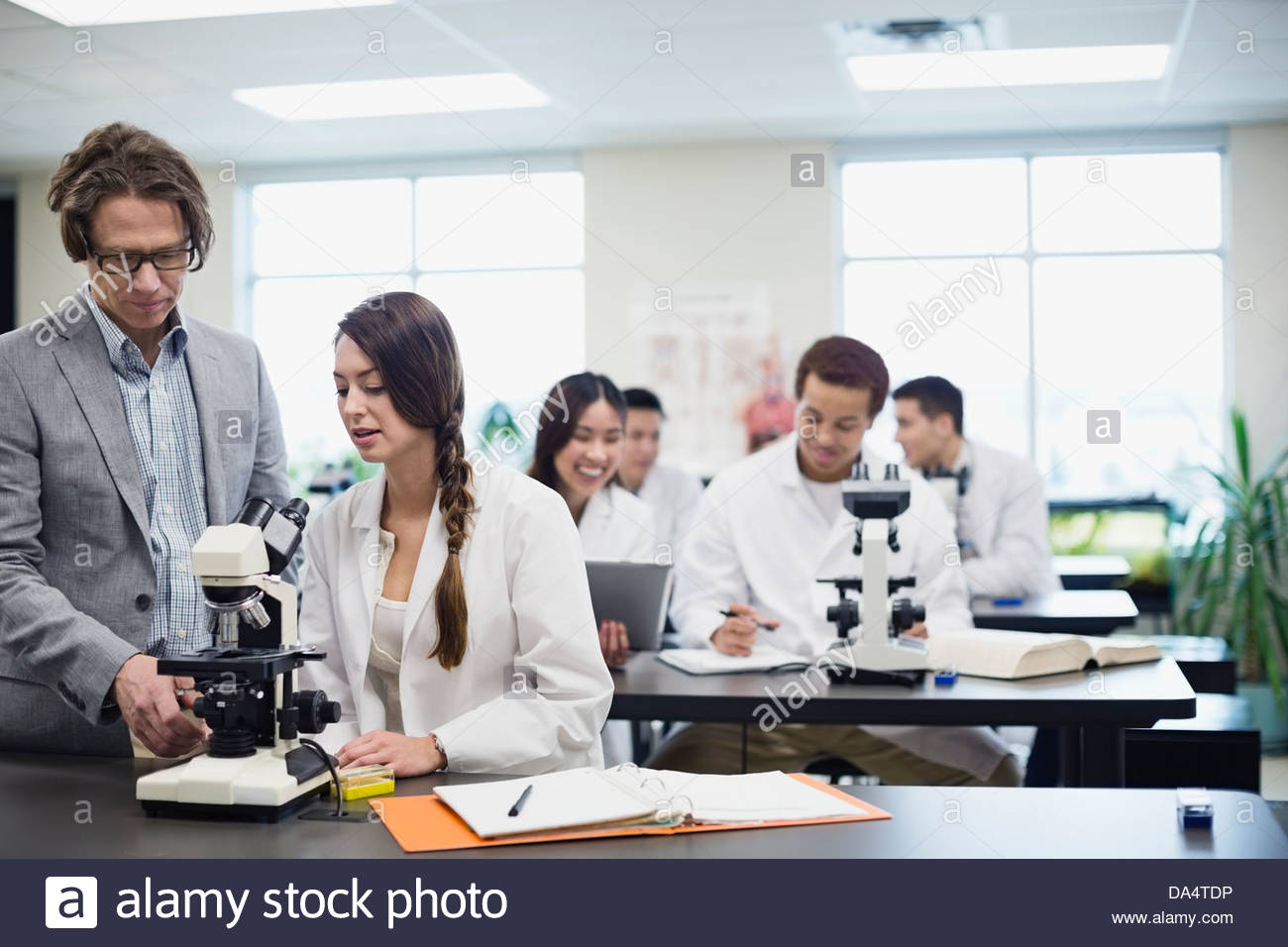 Professor helping female student with microscope in science lab Stock ...