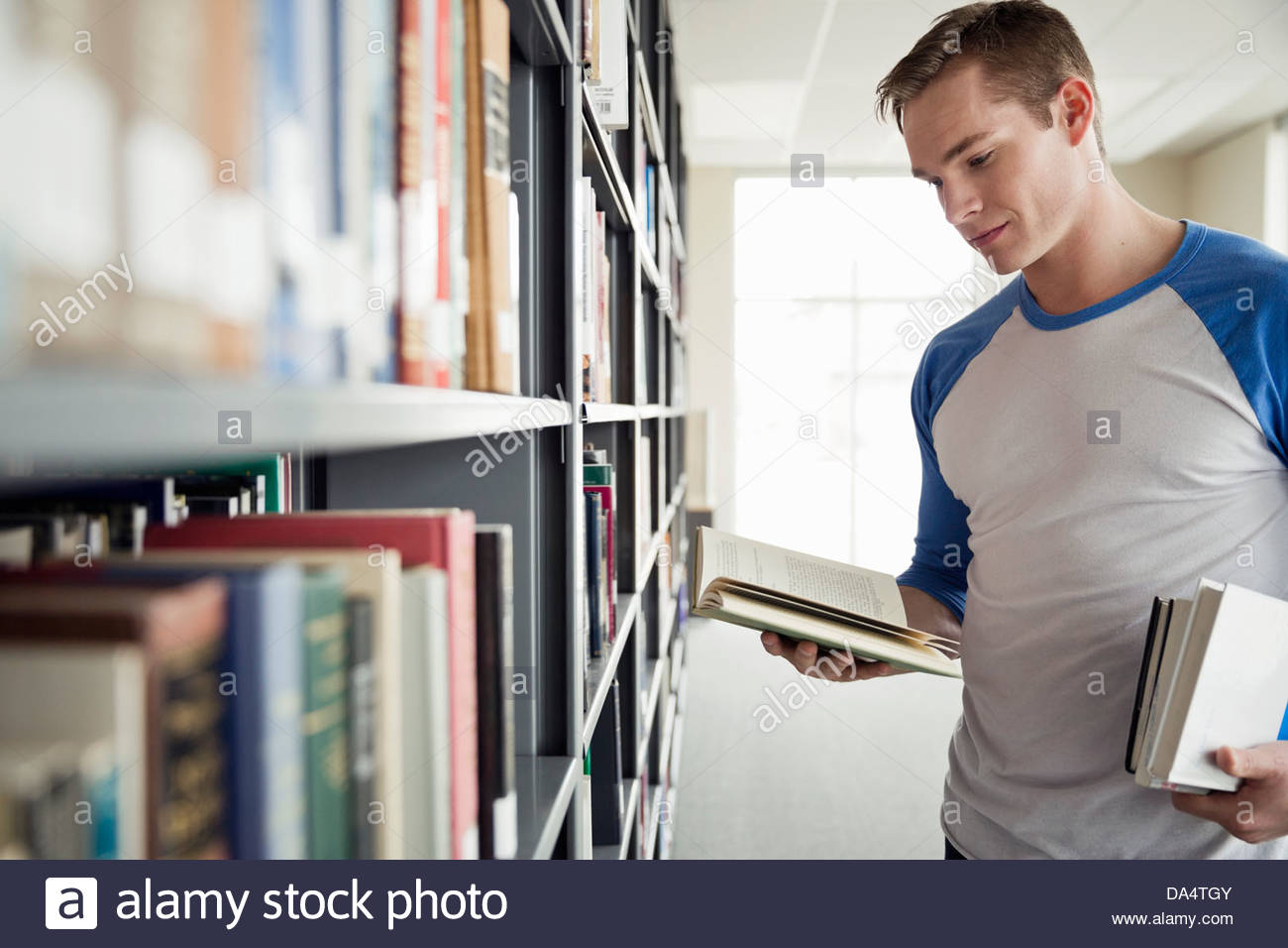 Male student choosing books in college library Stock Photo - Alamy